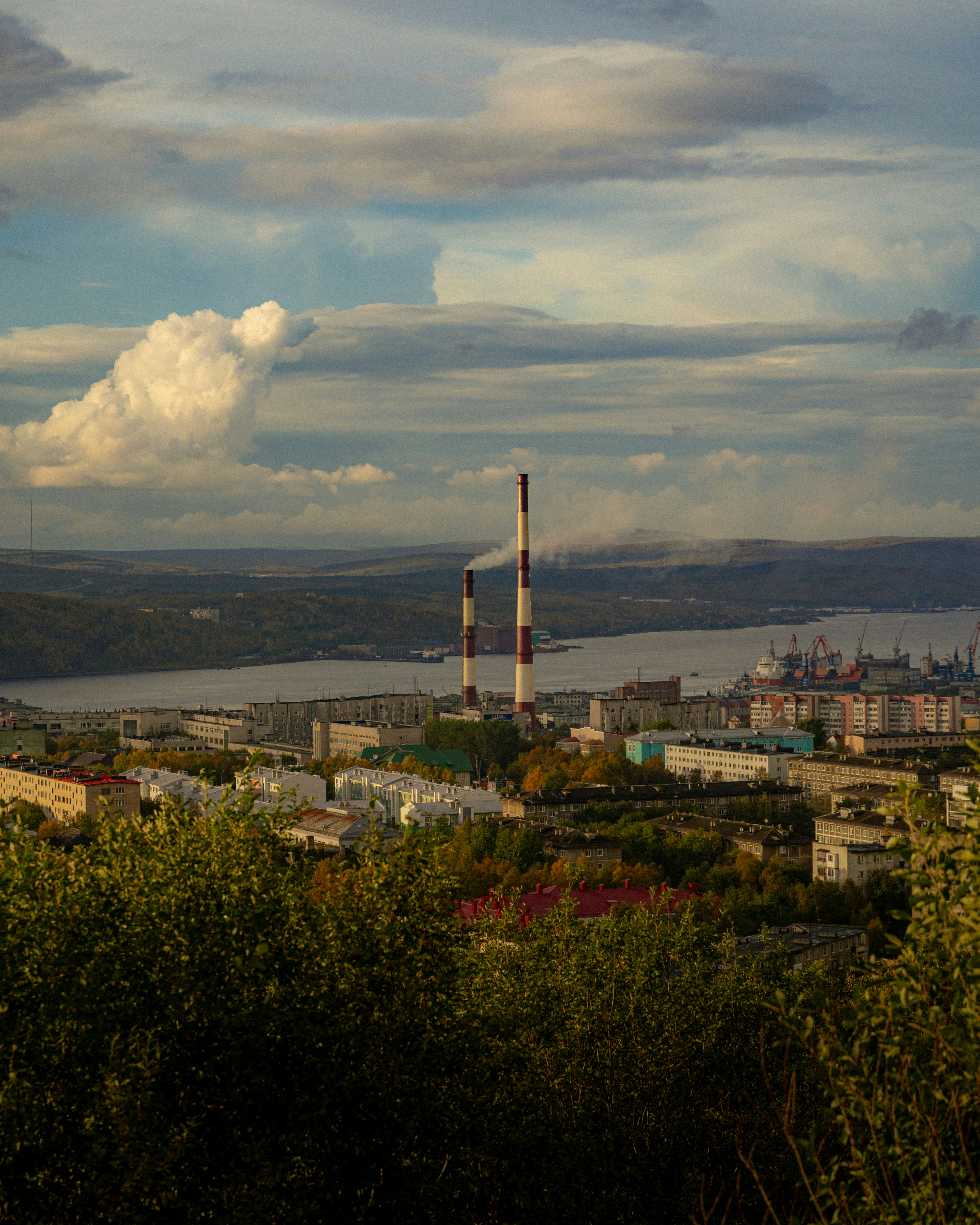 Industrial city with smoking chimneys by the water.