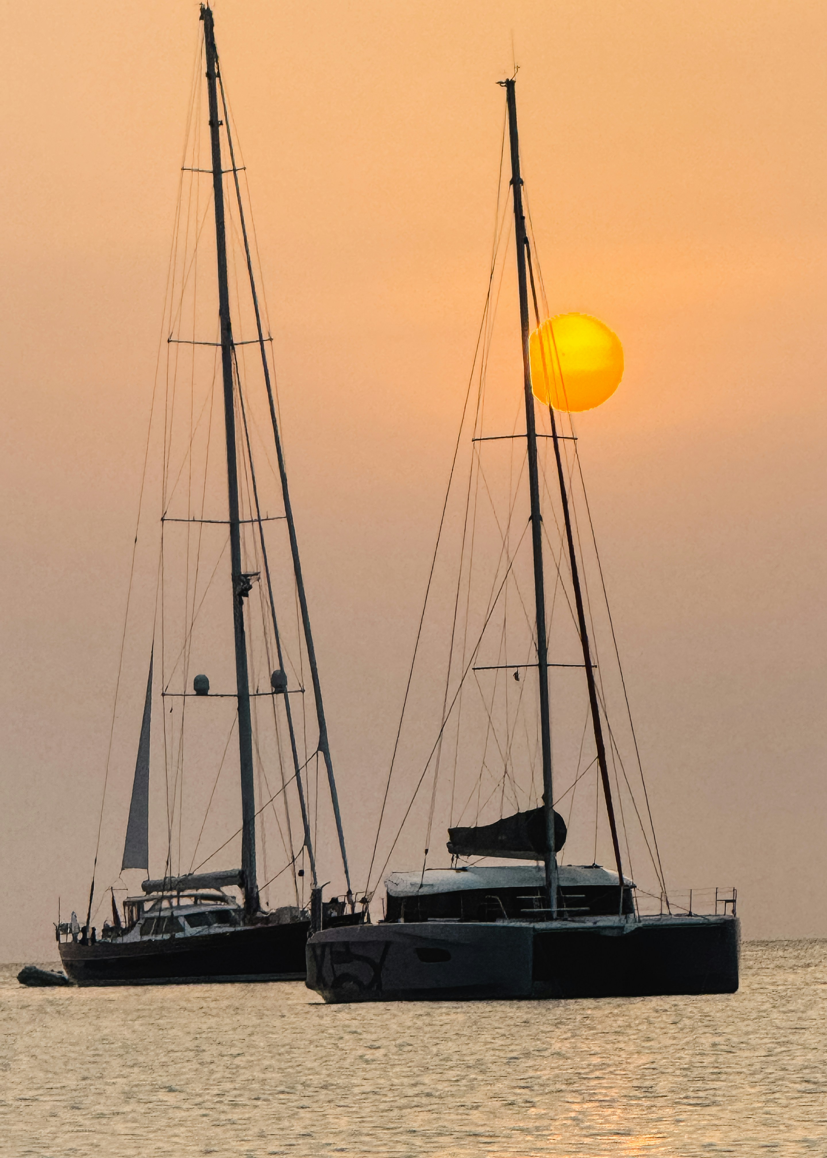 Two sailboats at sunset on the ocean