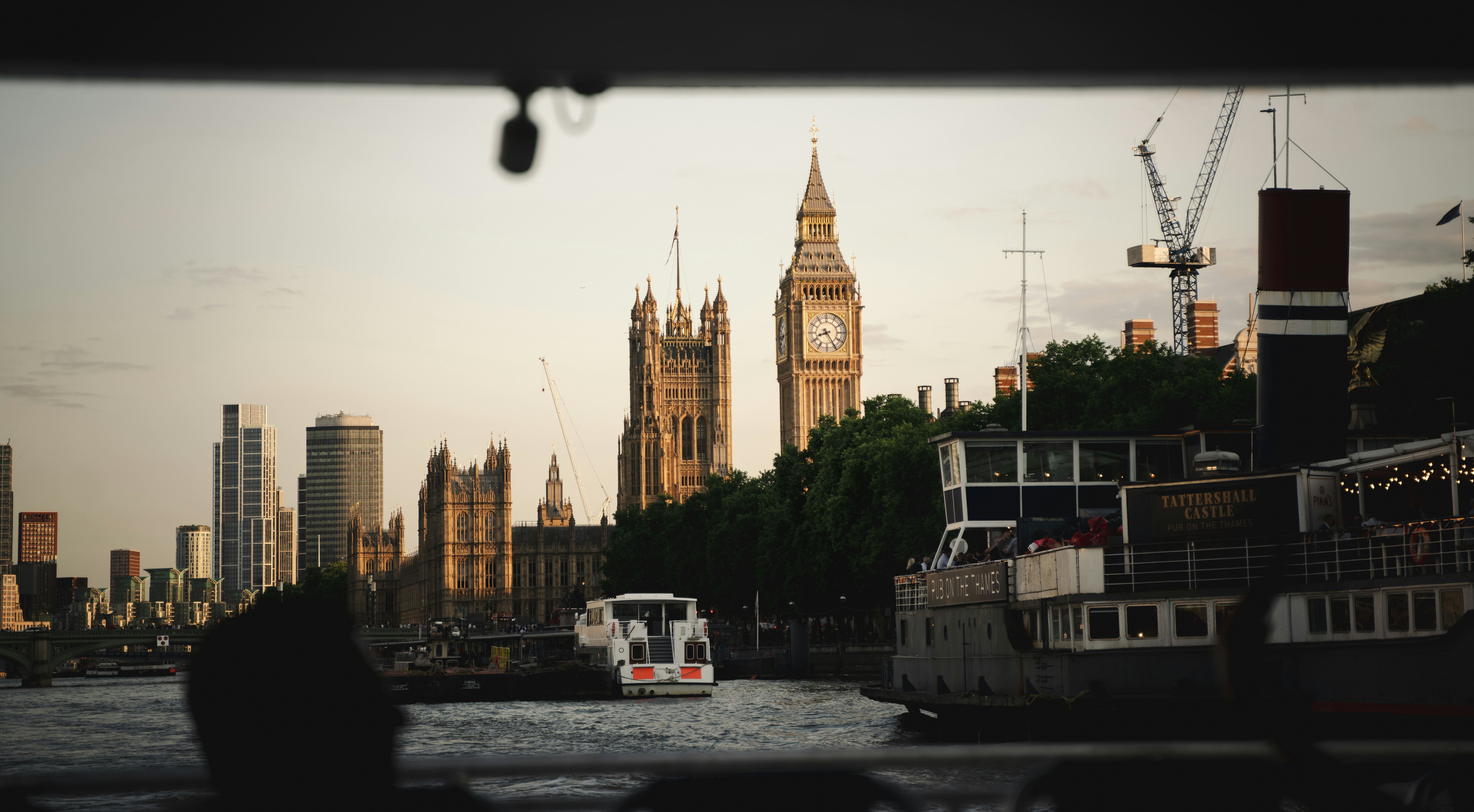 Big ben and river thames with boats at sunset