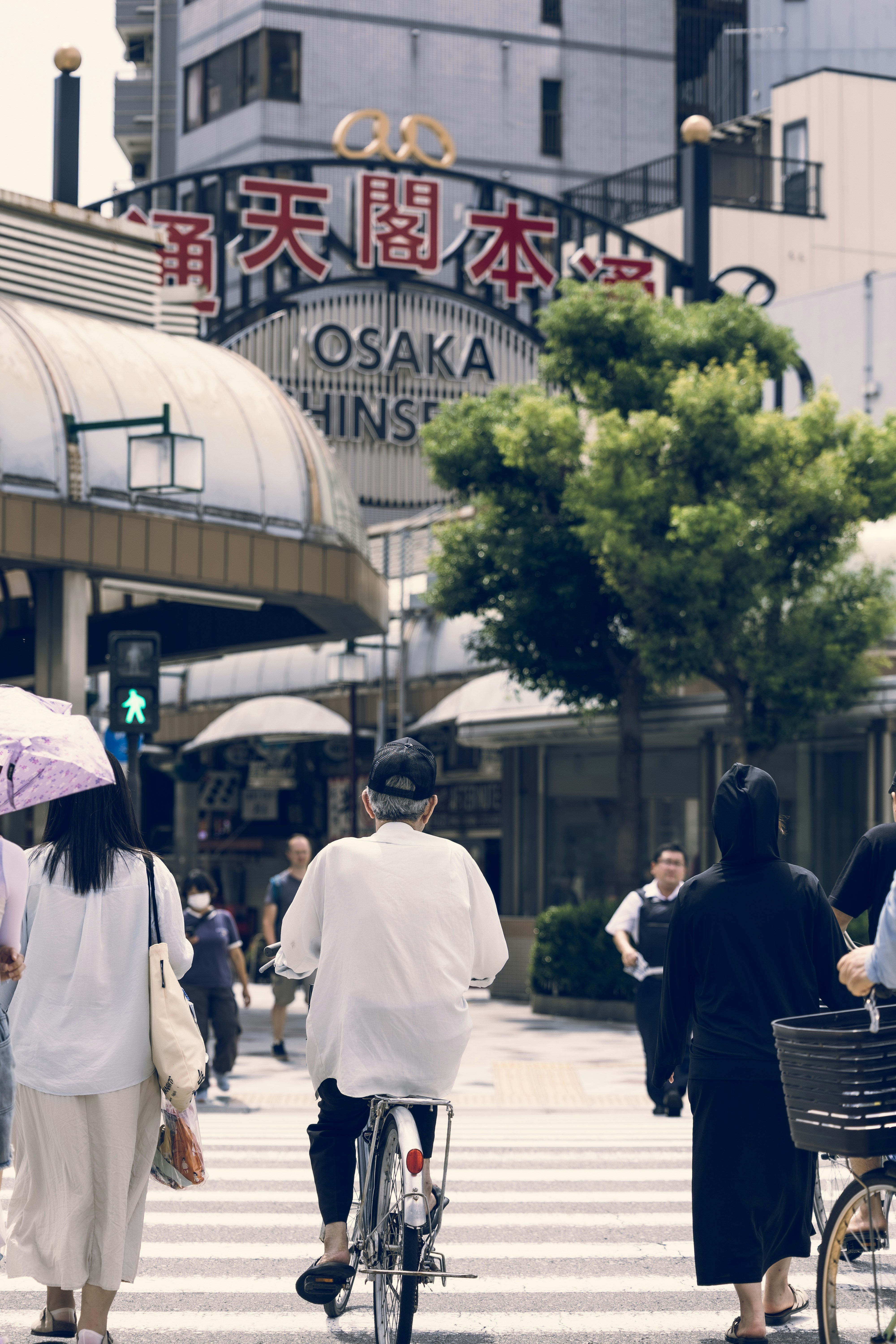 People crossing street in front of osaka signage