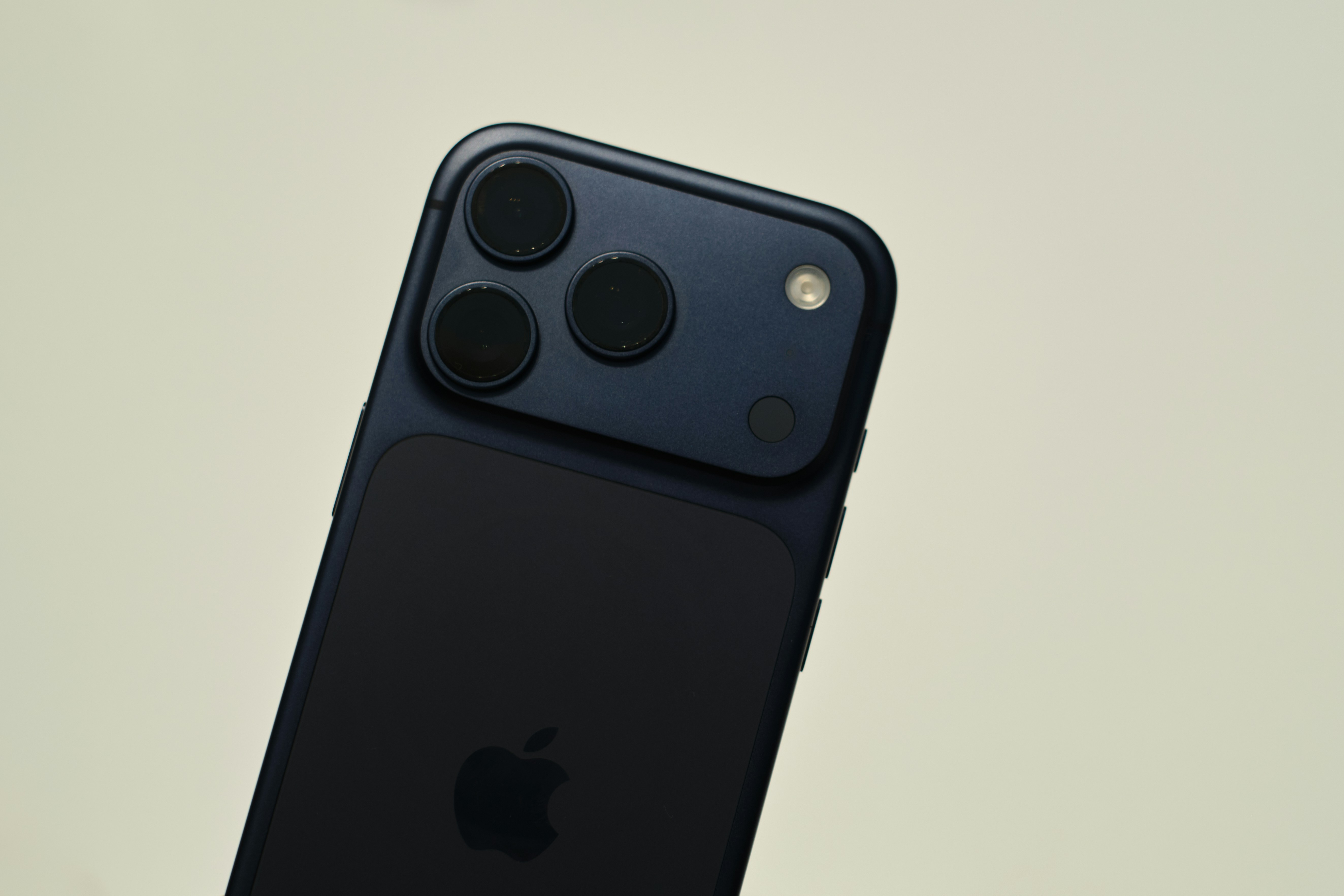 Close-up of dark smartphone camera lenses and apple logo.
