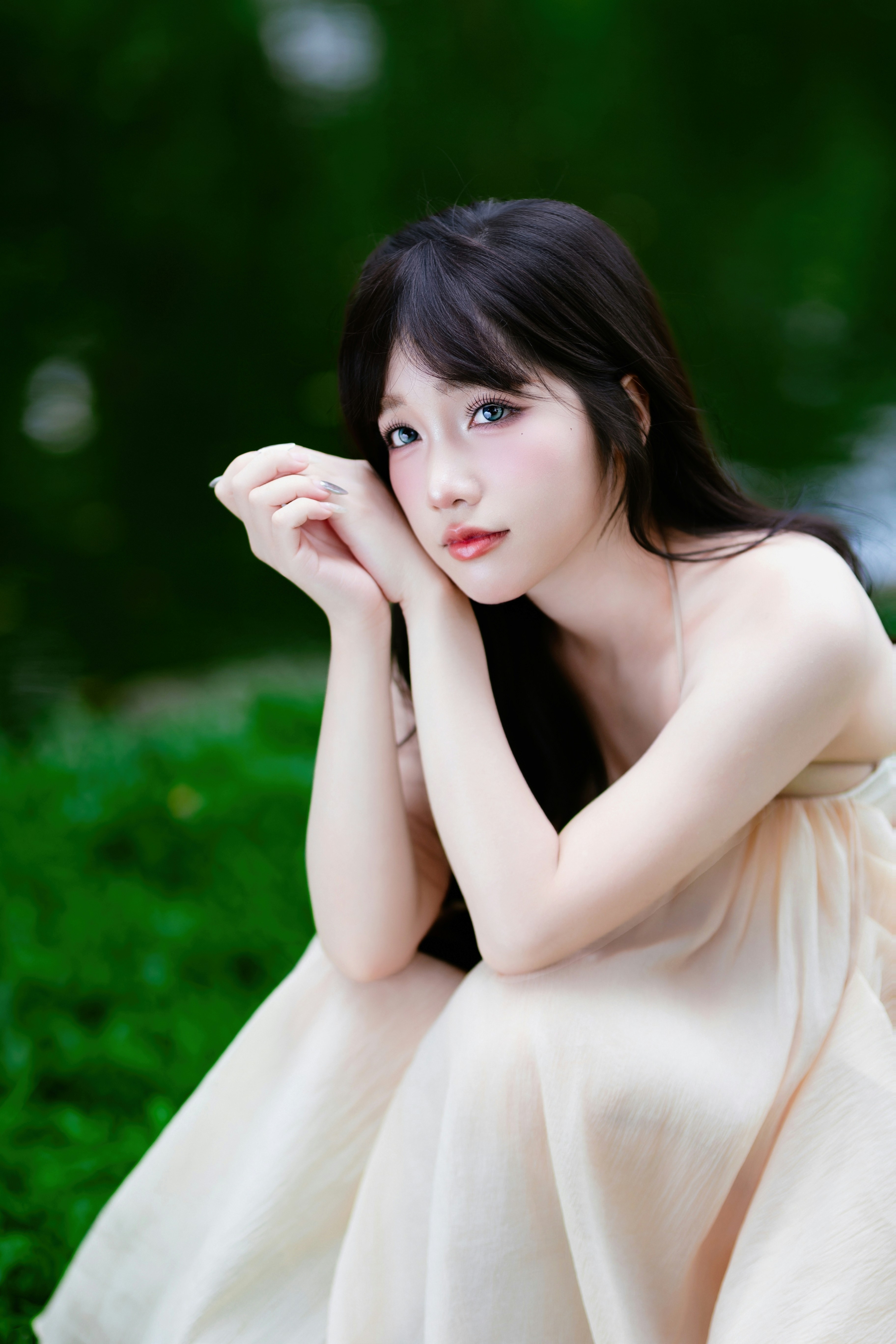 Young woman resting her chin on her hands, surrounded by lush greenery and soft reflections in water. The scene emanates tranquility.
