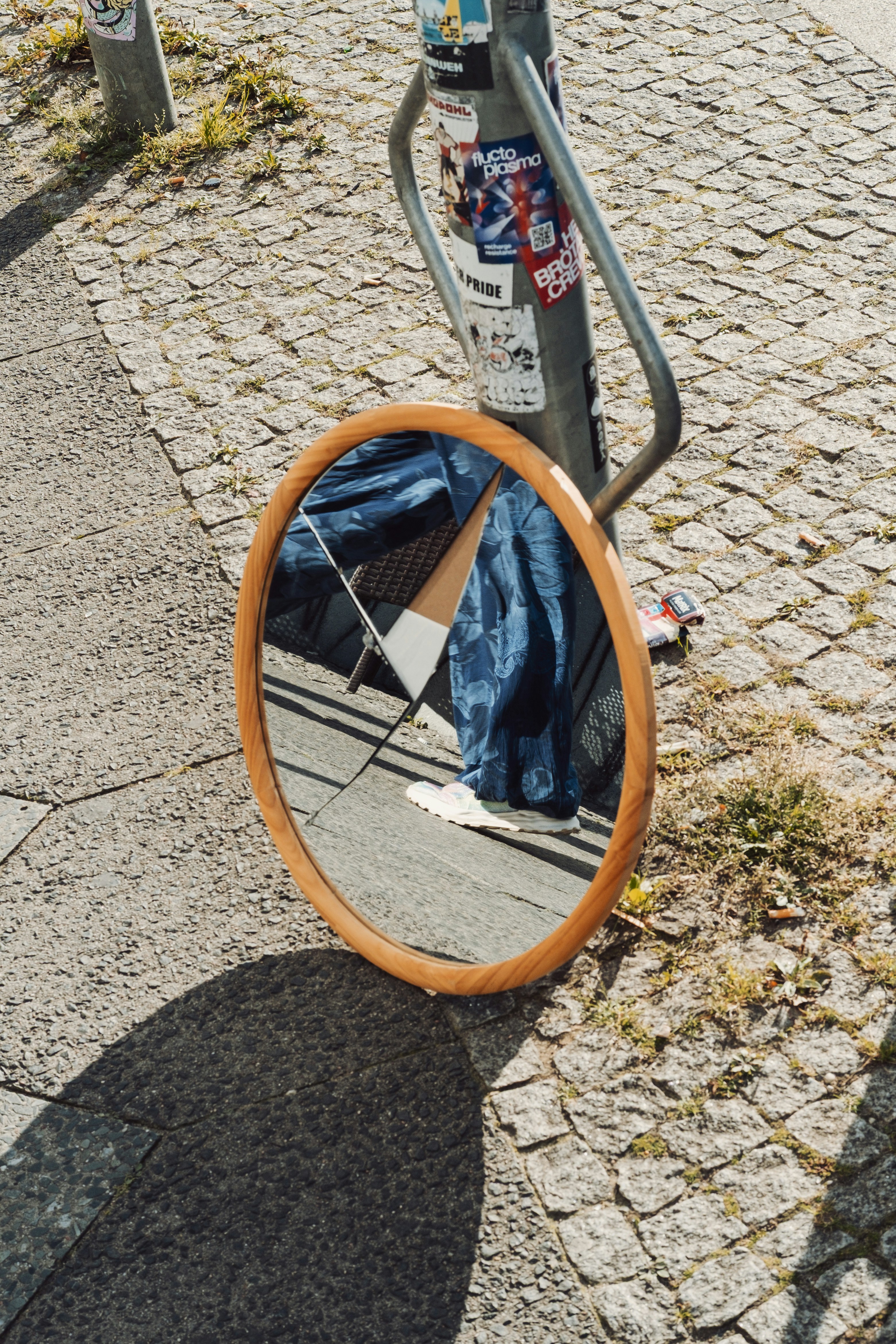 Broken mirror with wooden frame on cobblestone street
