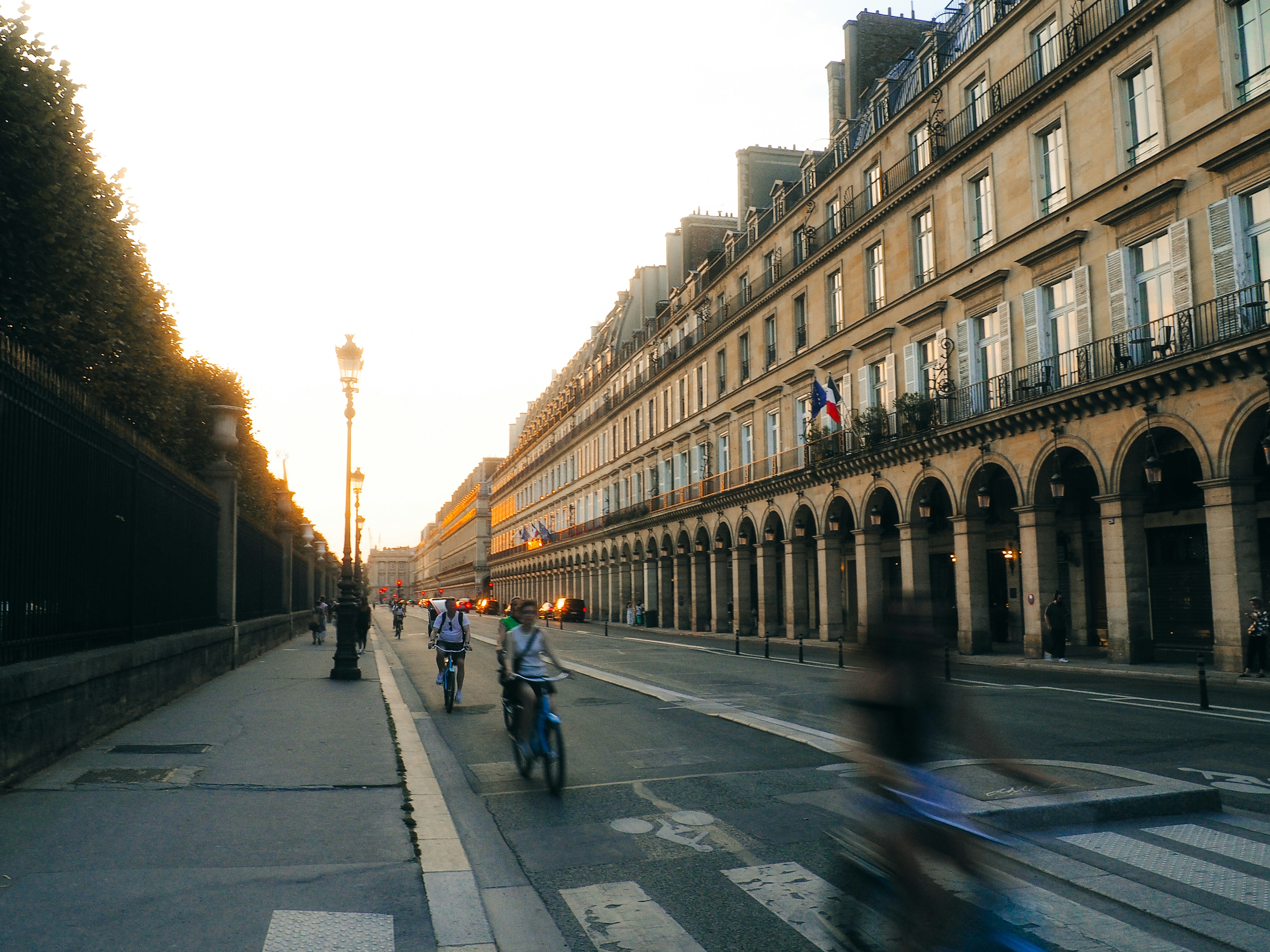 The Eiffel Tower by night is not just a landmark, it’s a glowing icon of love, passion, and intimacy. This photo shows a couple enjoying romantic Paris vibes, surrounded by golden lights, night photography, and honeymoon energy. With the Seine reflections, the sparkling tower, and the gentle embrace of lovers, it becomes a postcard of romance, marriage proposals, engagement dreams, and wedding goals. It’s a mix of travel inspiration, couple lifestyle, Parisian charm, and relationship magic. Perfect for anyone who dreams of Paris love stories, iconic photography, and cinematic romance under the | People cycling on a street in paris at sunset