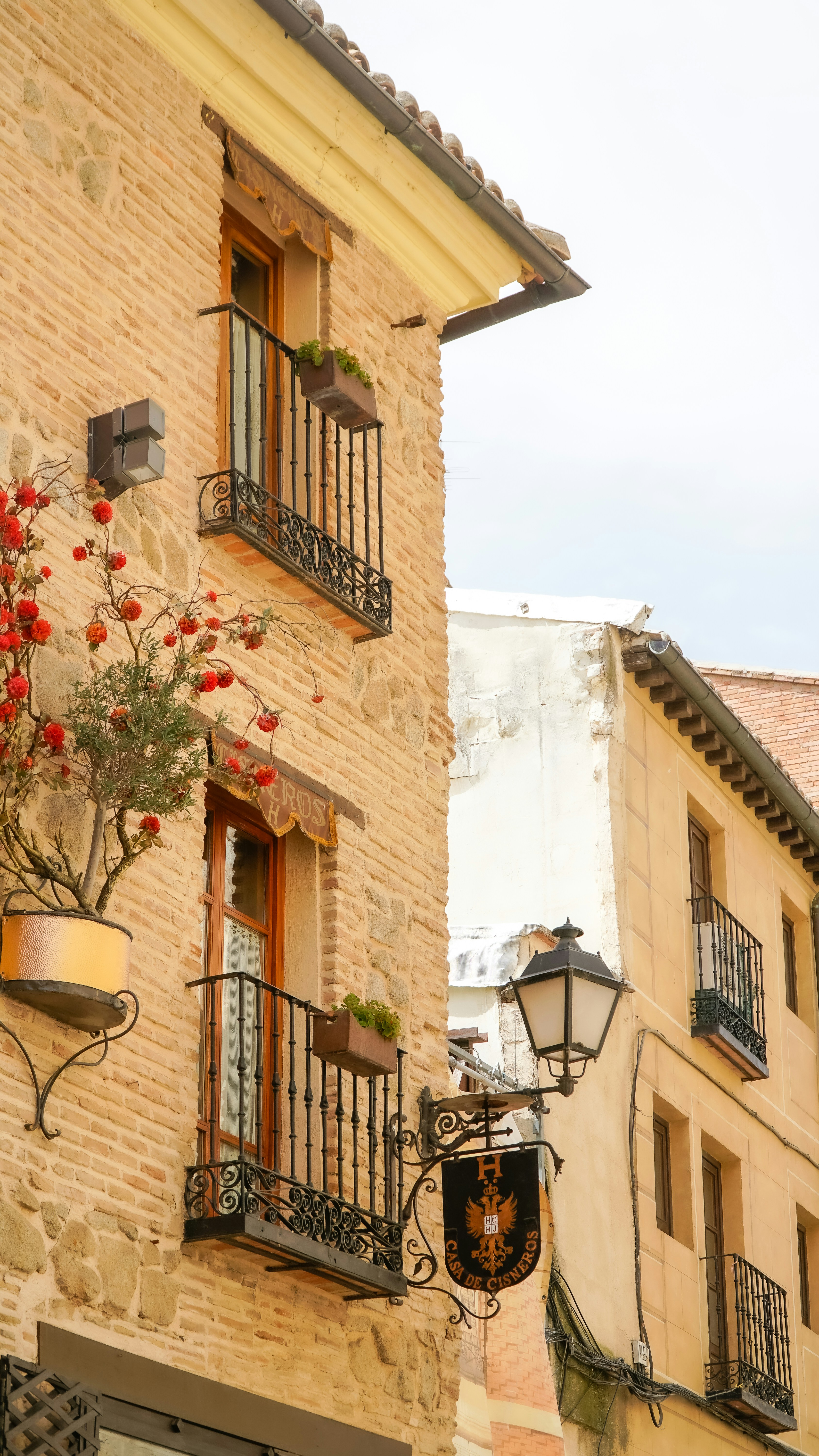 Ornate balconies on a brick building with red flowers.