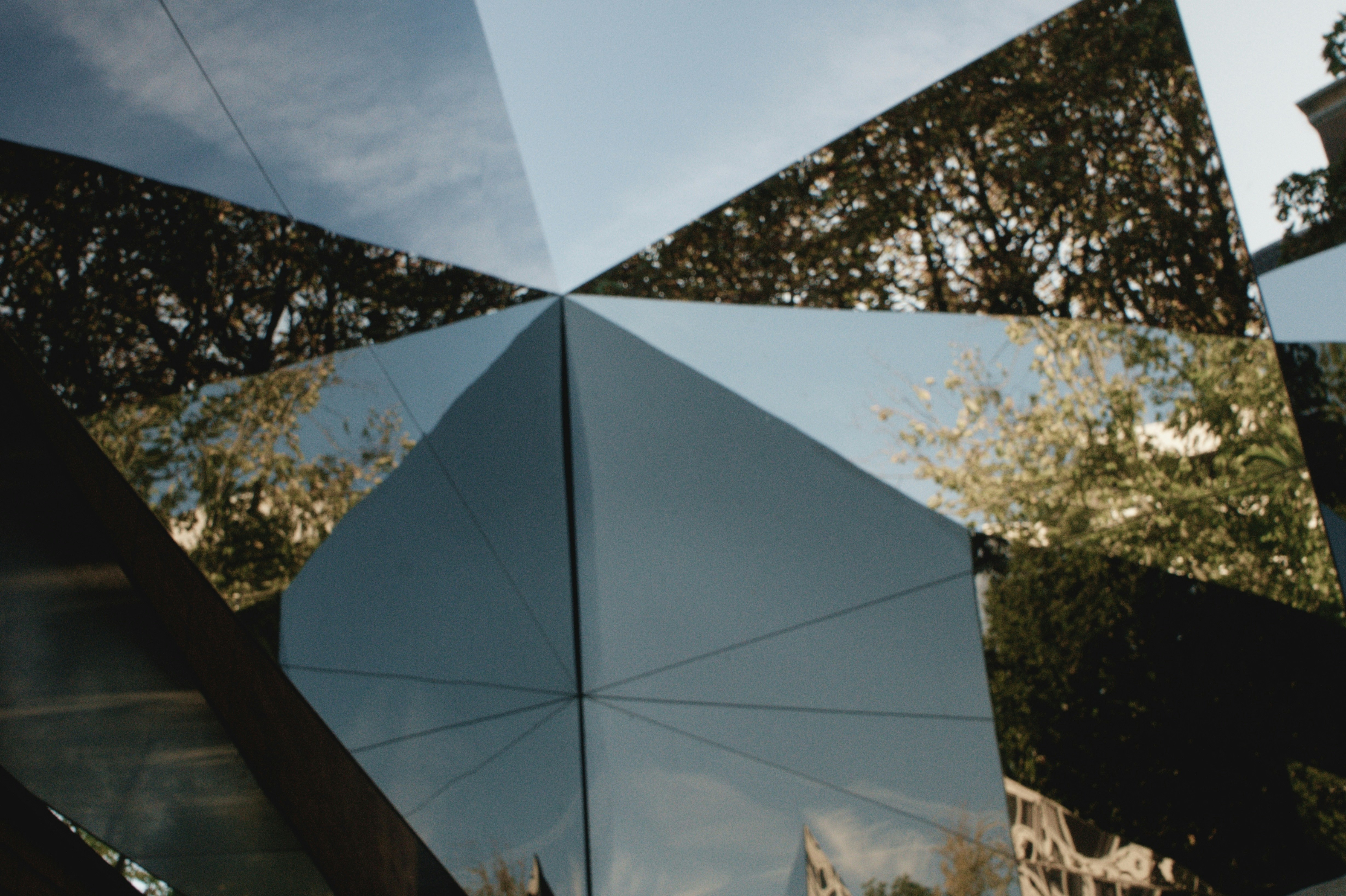 Geometric mirrored sculpture reflecting trees and sky