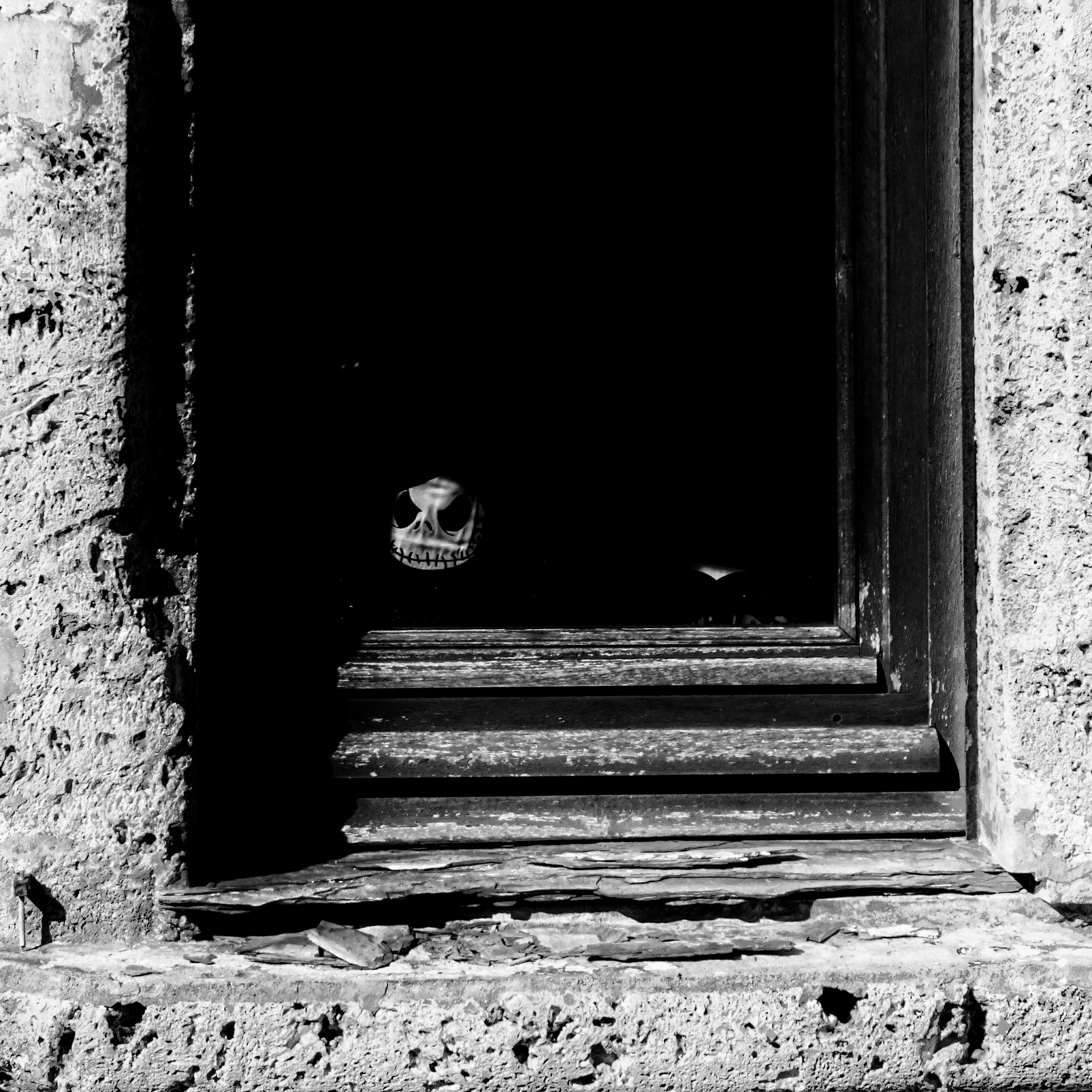 A dark, weathered window frame with stone sill.