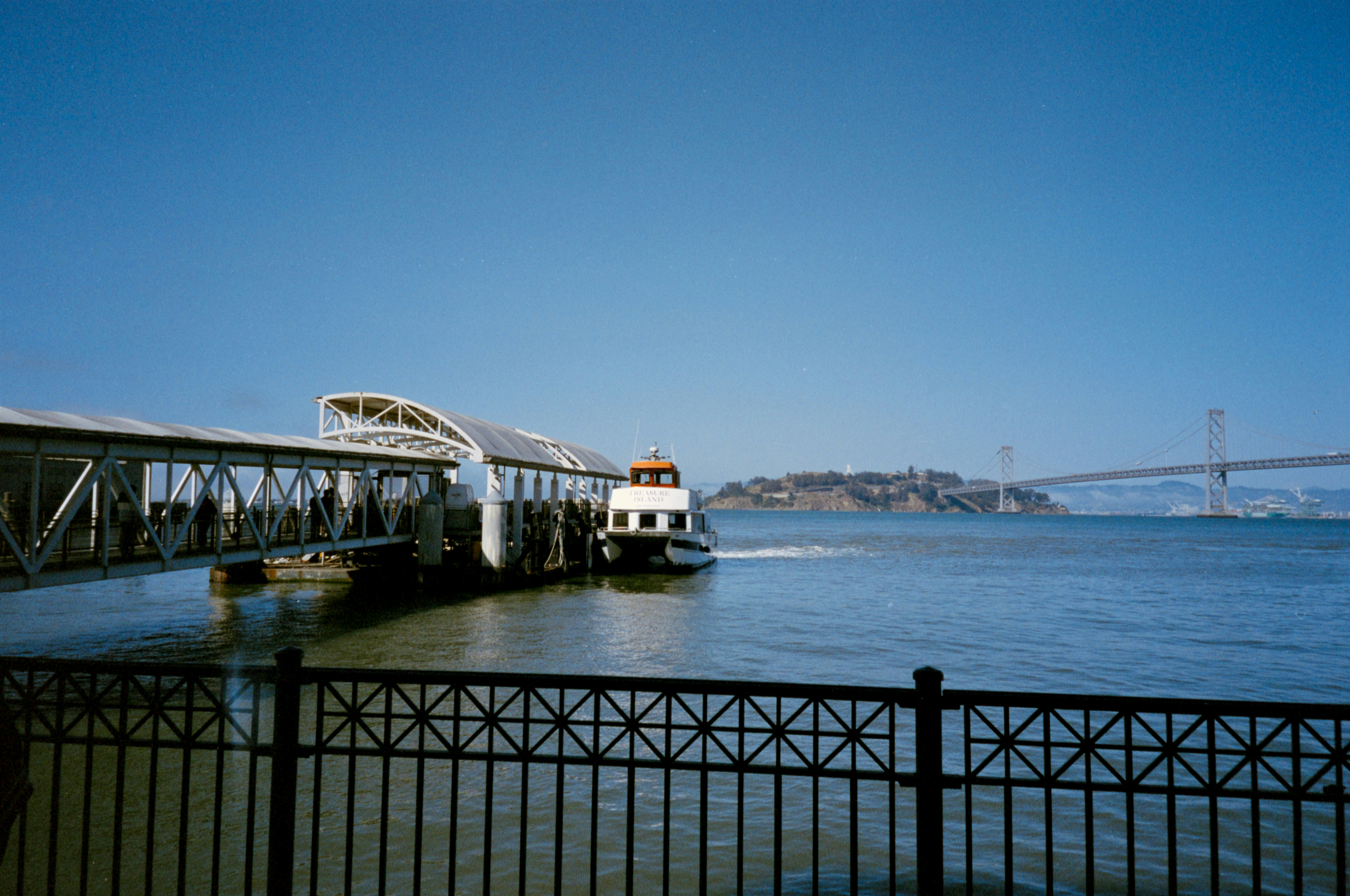 Ferry boat docked at a pier with bridge in background.