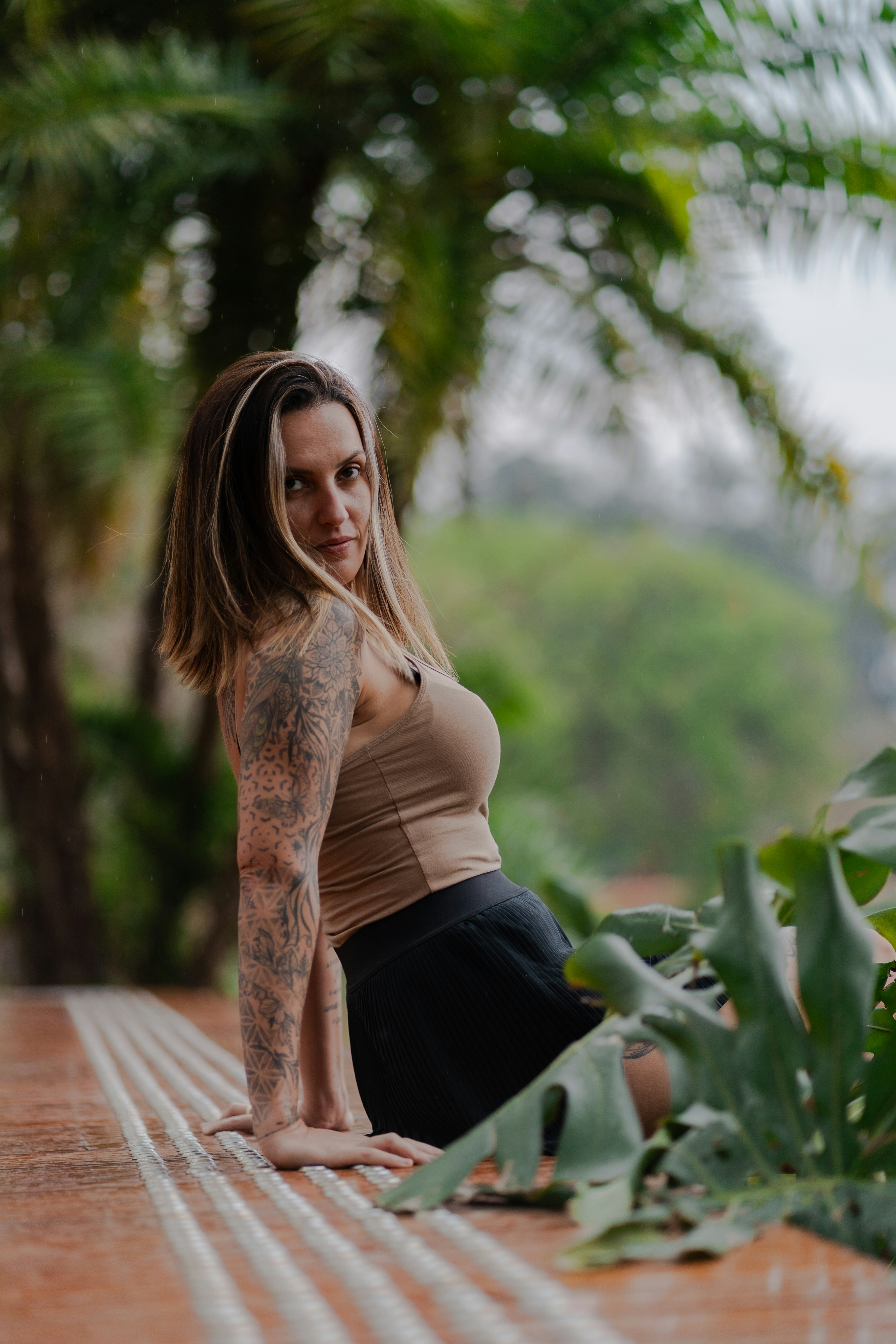 Woman with tattoos sitting outdoors near plants