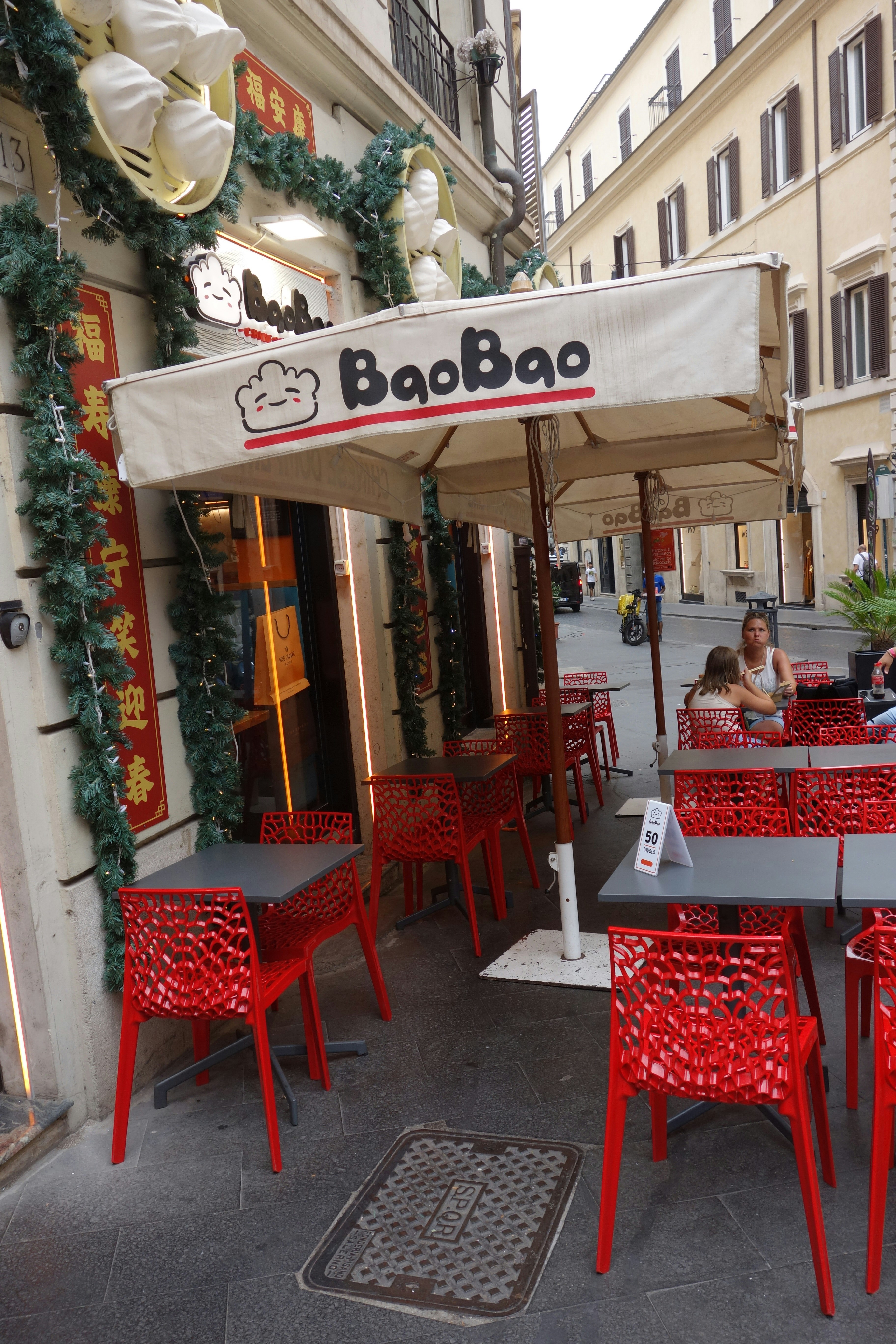 BaoBao Street Café: Sunlit Terrace with Red Chairs on a Quiet European Lane