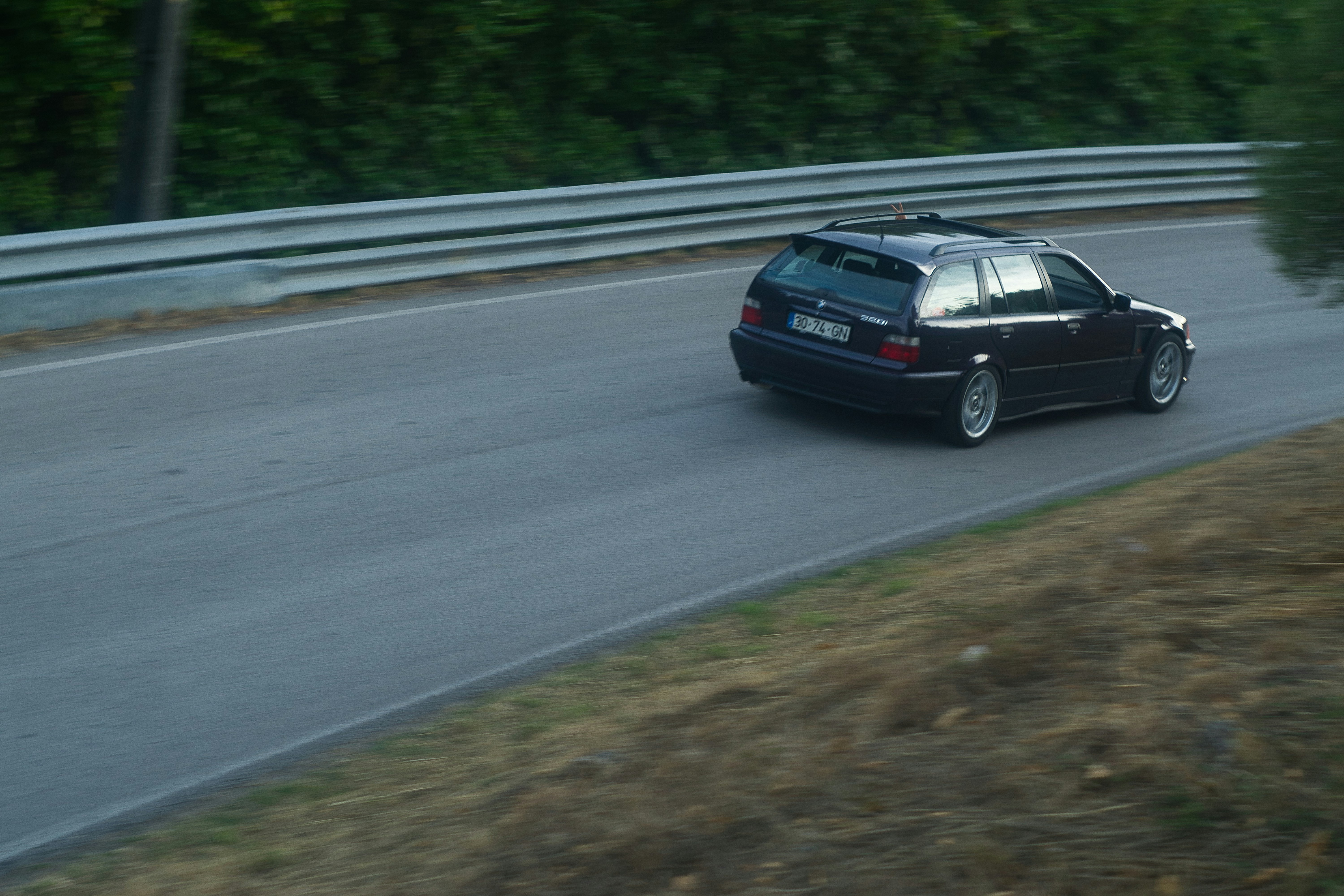Dark station wagon driving on a winding road.
