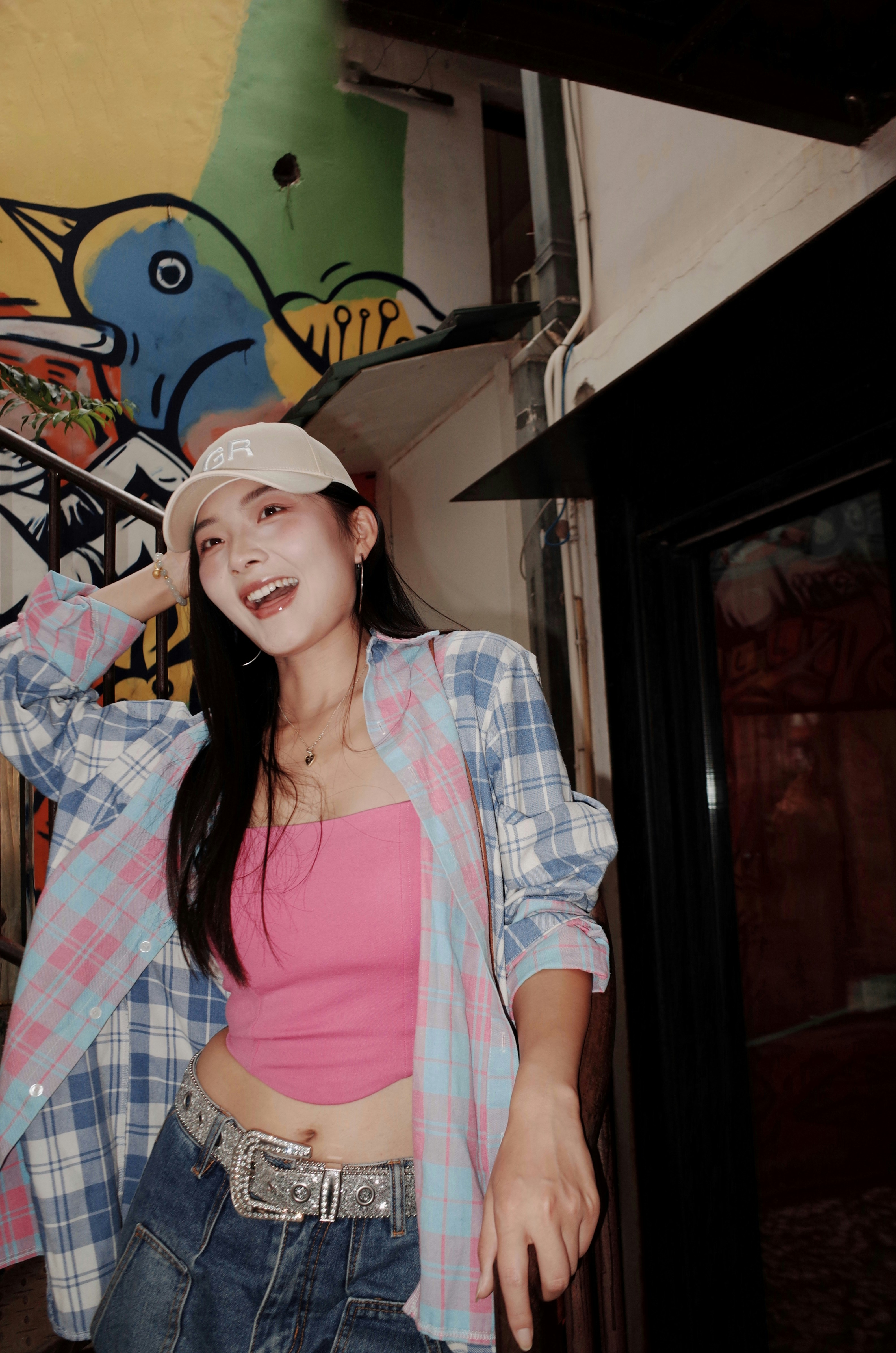 Young woman in cap and plaid shirt near graffiti