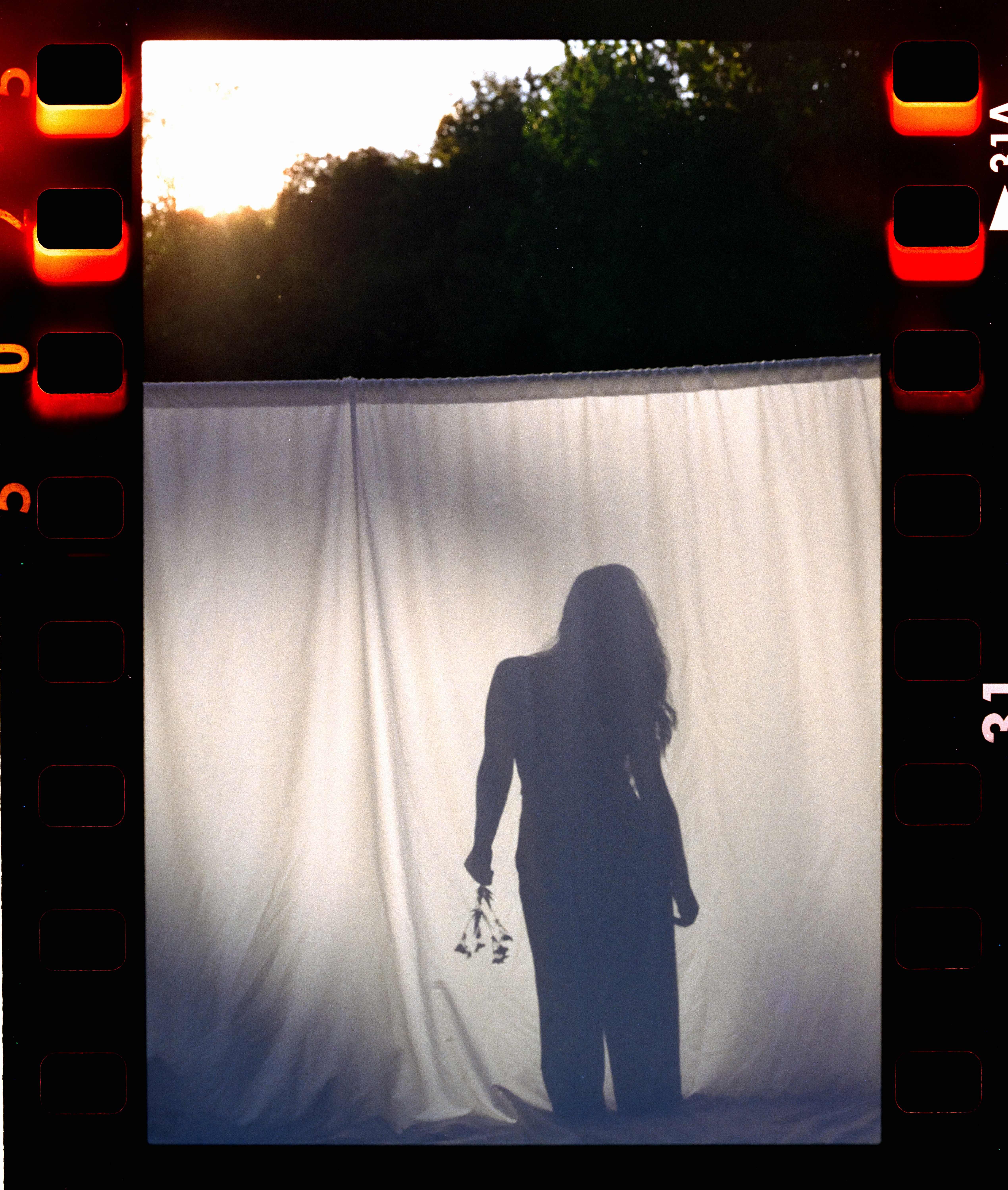 Silhouette of a woman holding keys against backlit curtain