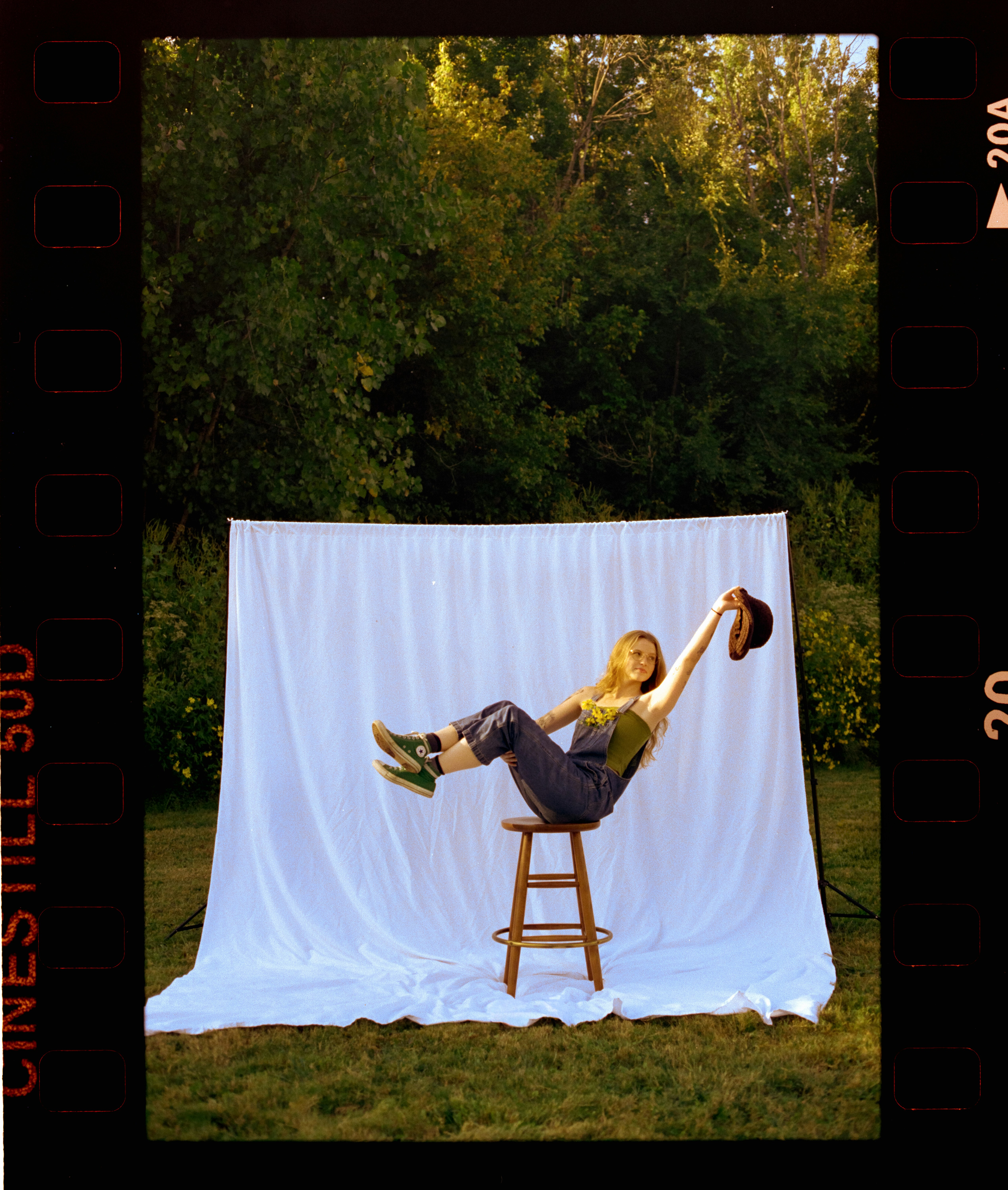Outdoor Studio Portrait: A Woman Relaxed on a Stool Before White Backdrop