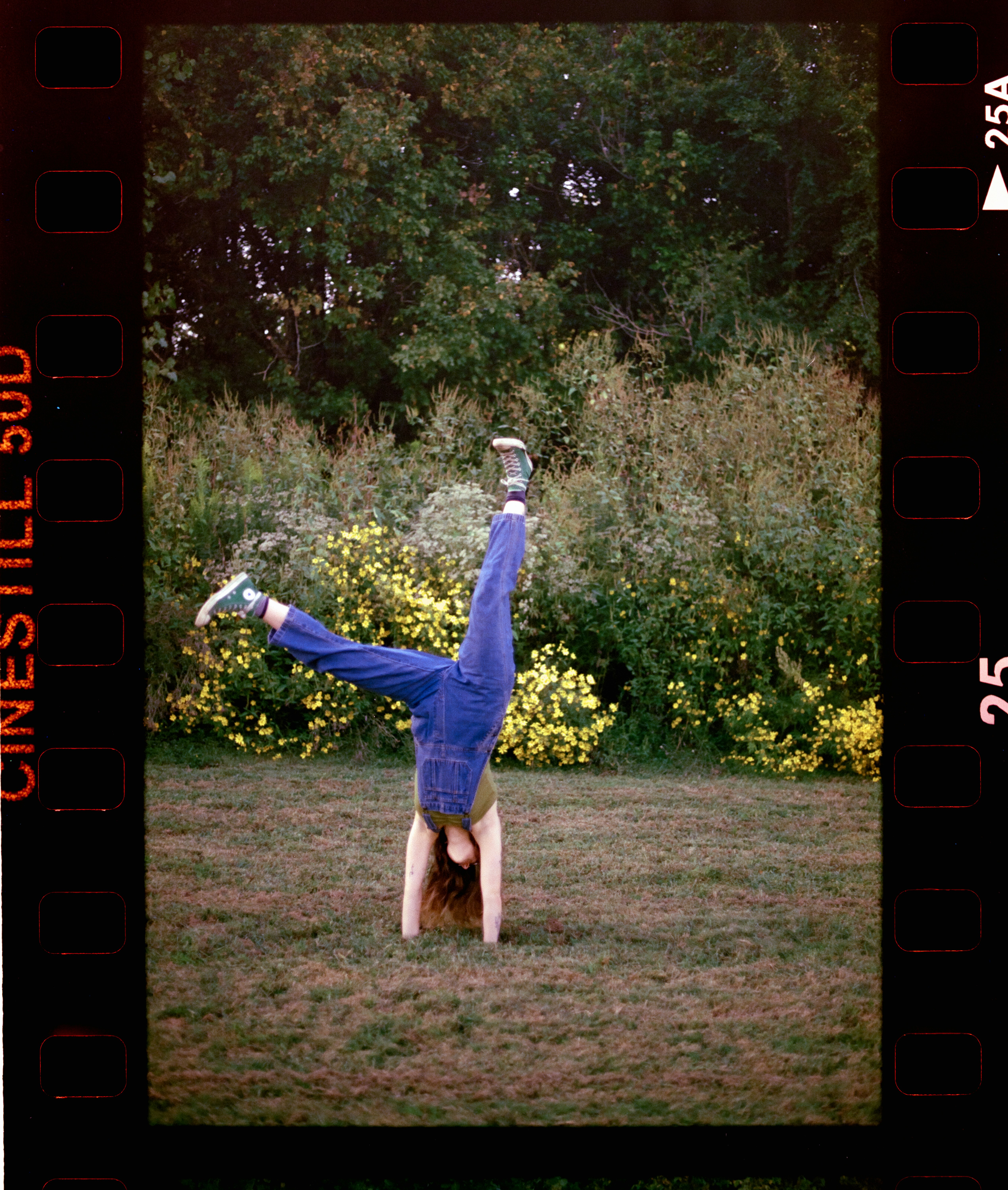 Young person doing a cartwheel in a grassy field.