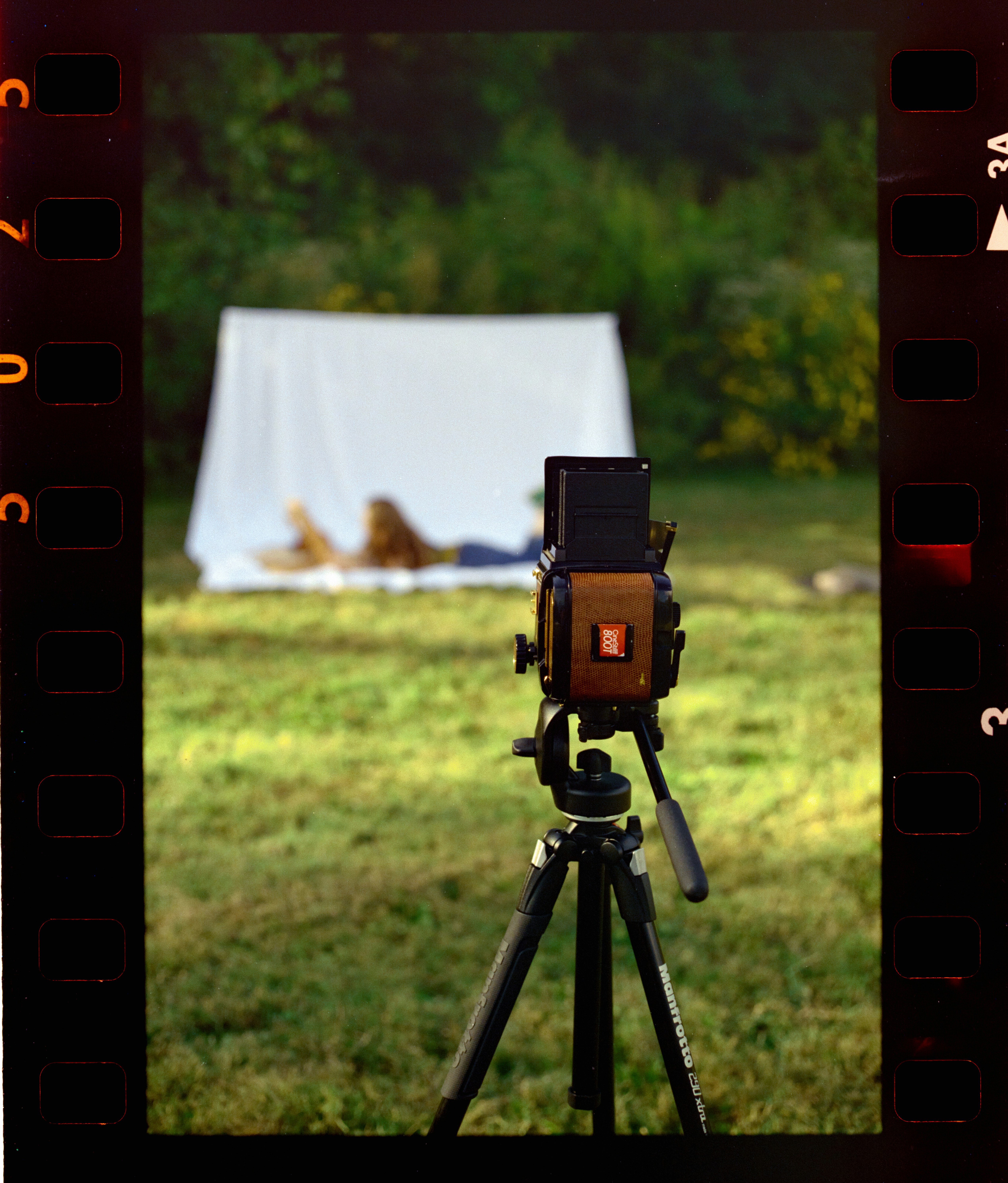 Vintage camera on tripod photographing person on sheet