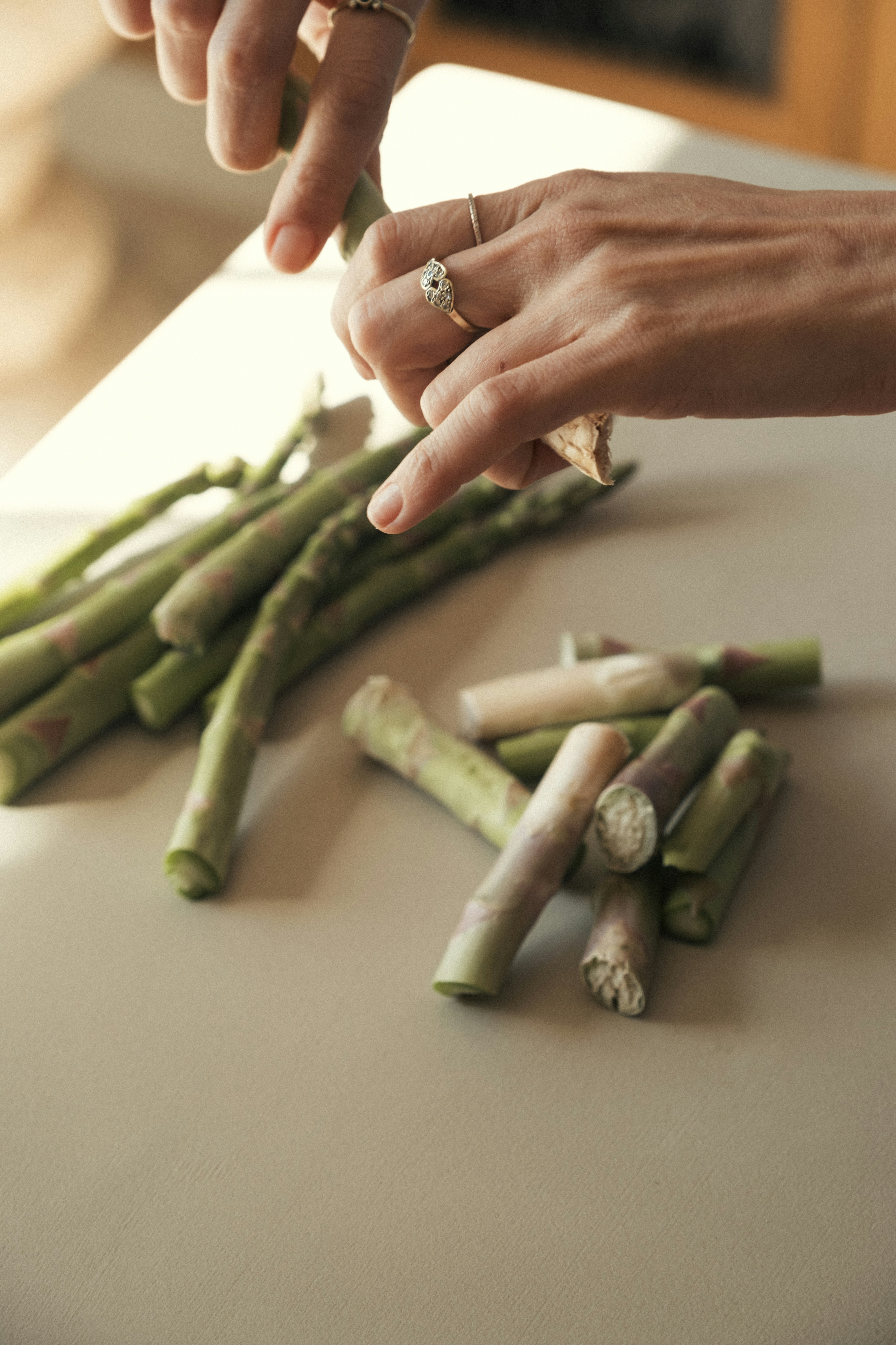 Hands trimming fresh asparagus spears on a counter.