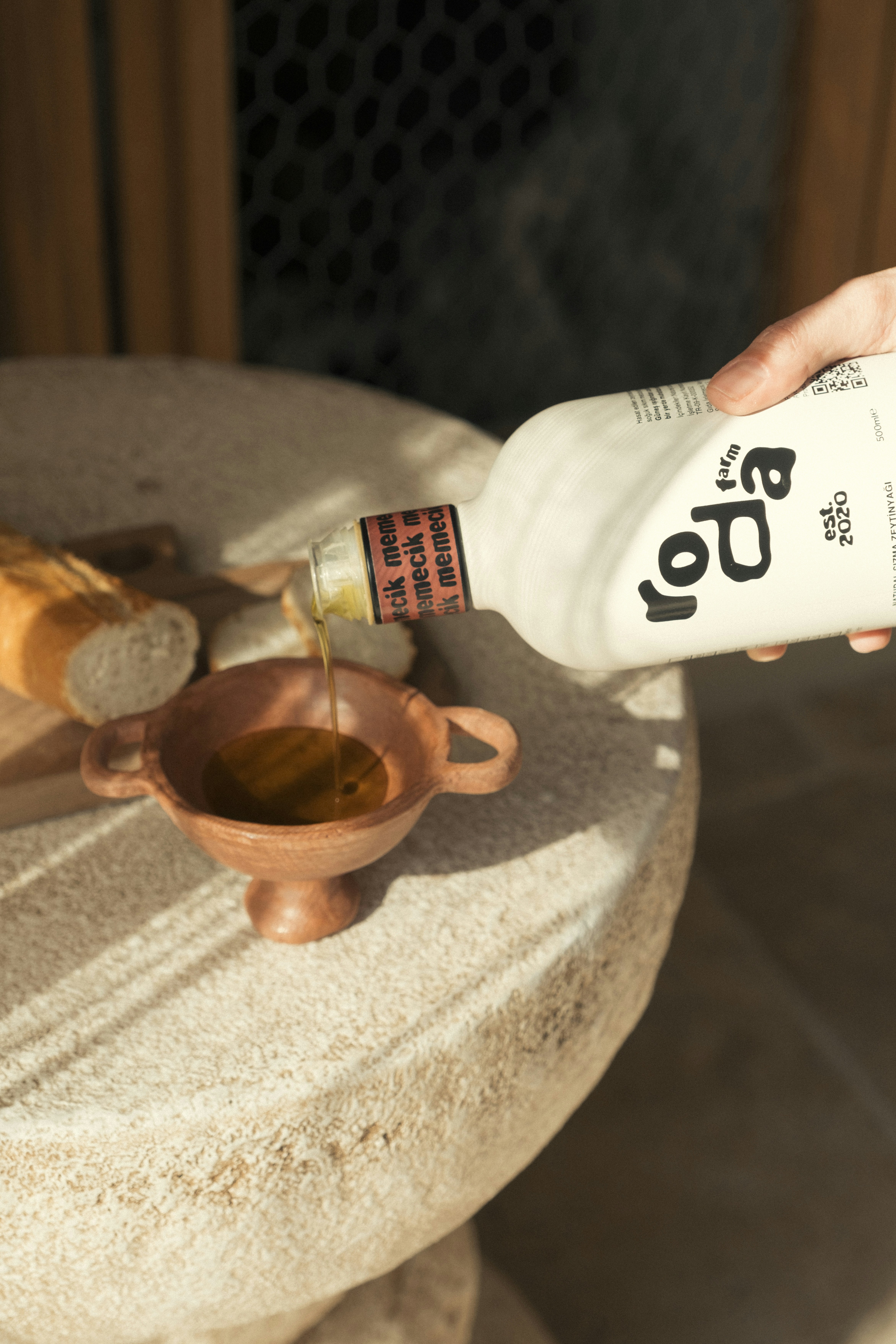 Sunlit Olive Oil Pour Into a Tiny Terracotta Cup on a Rough Stone Table