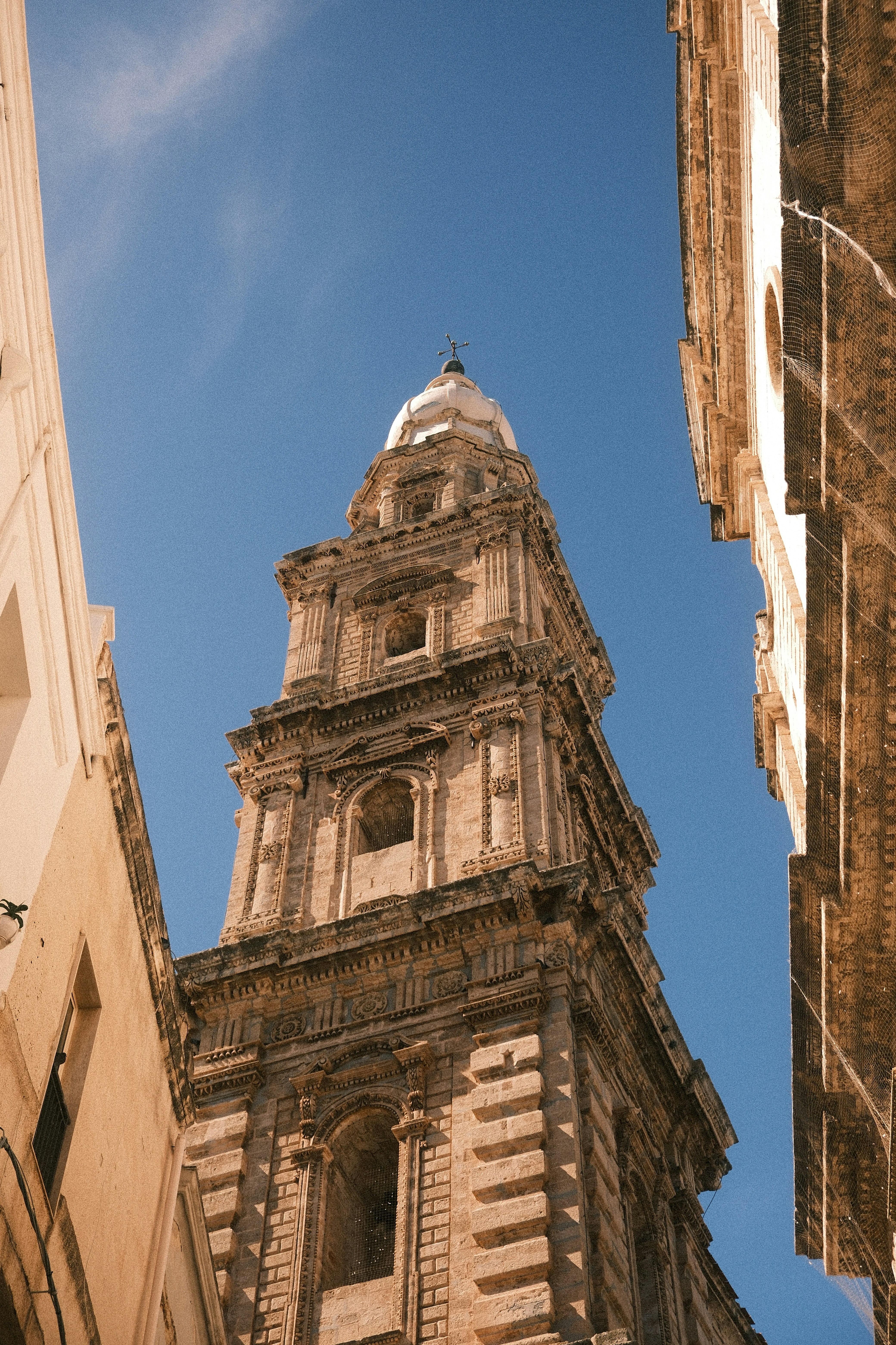 Historic stone bell tower against a clear blue sky.