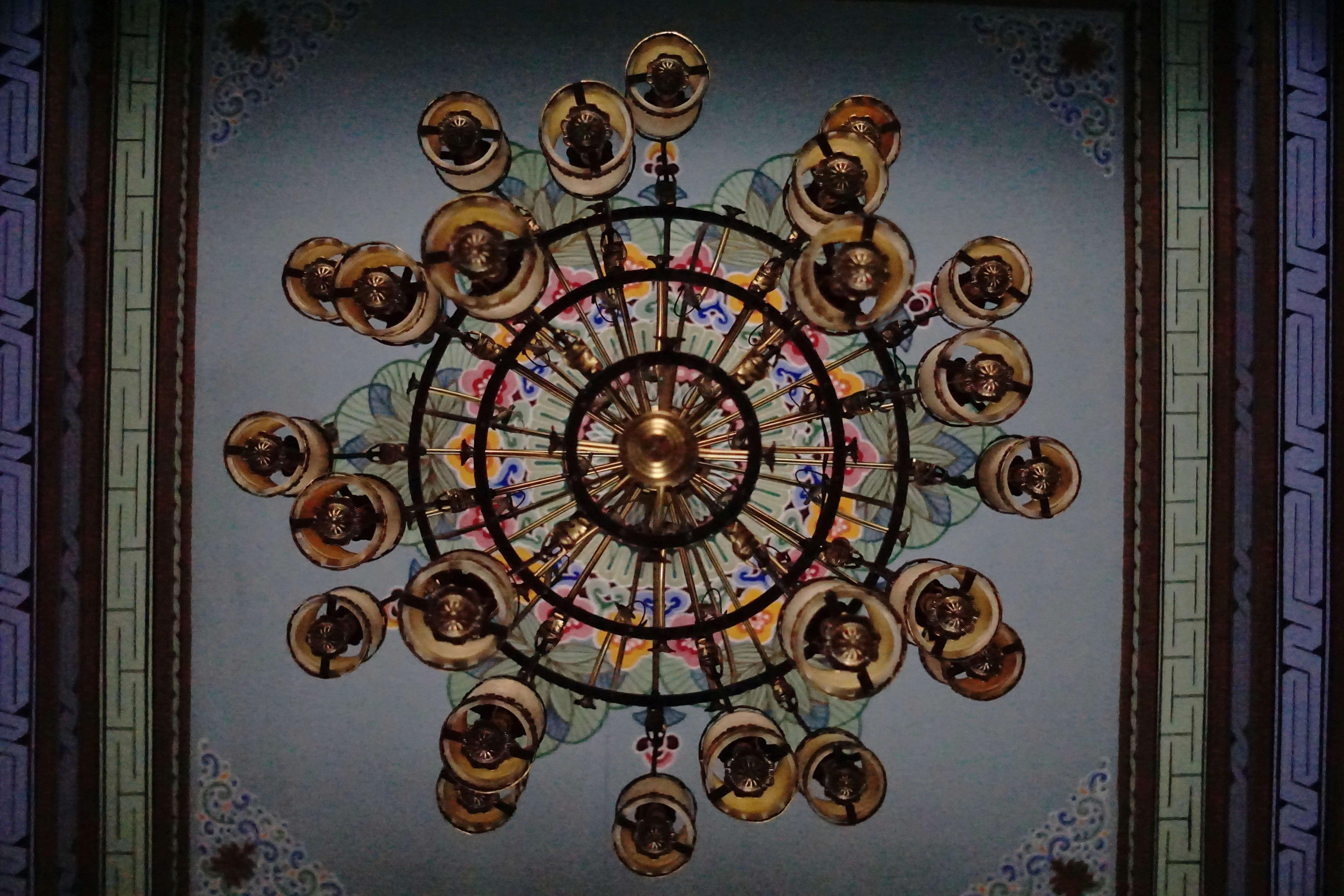 Ornate chandelier with stained glass ceiling detail hanging from ceiling