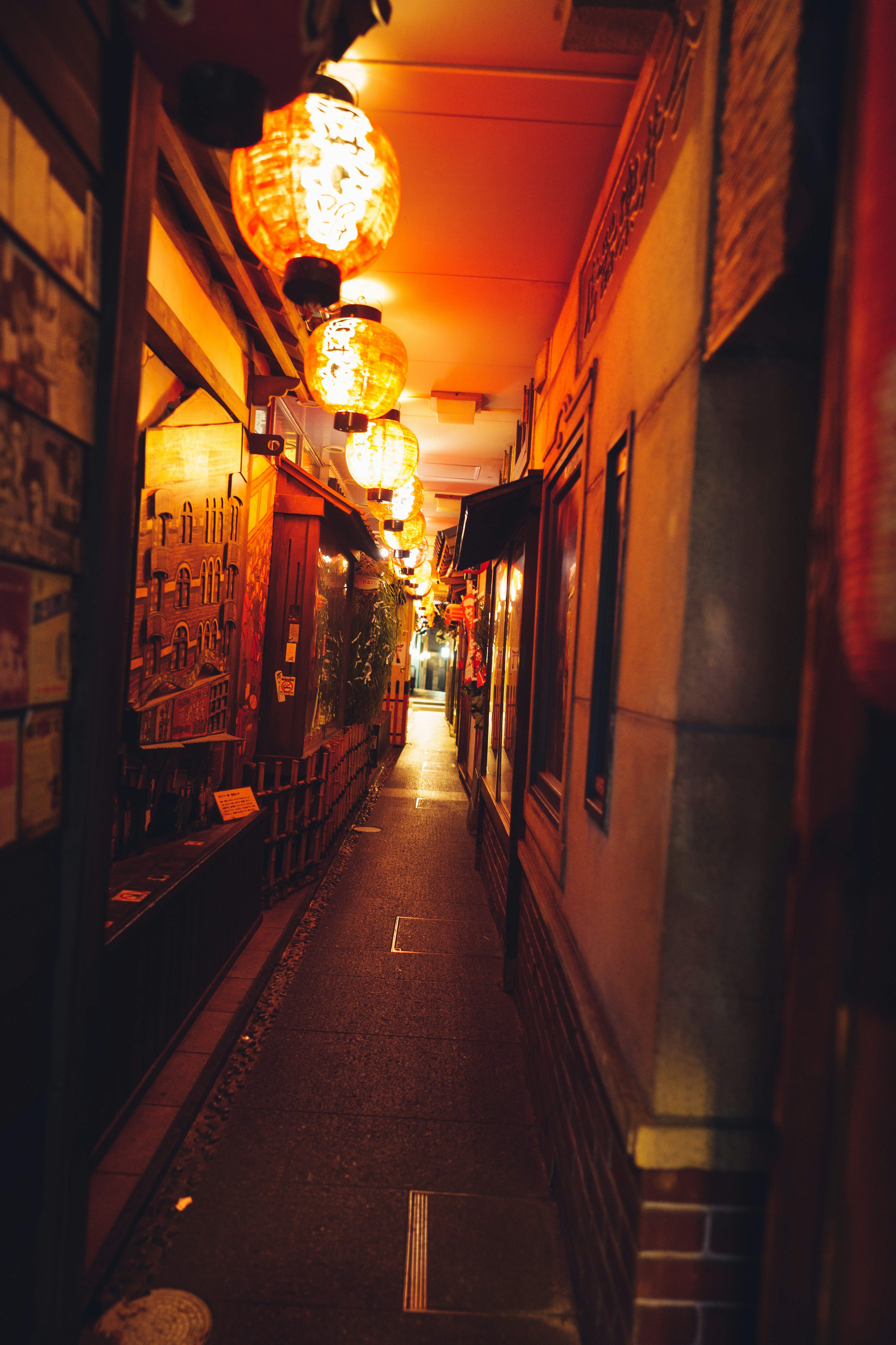 Narrow alleyway illuminated by traditional lanterns at night