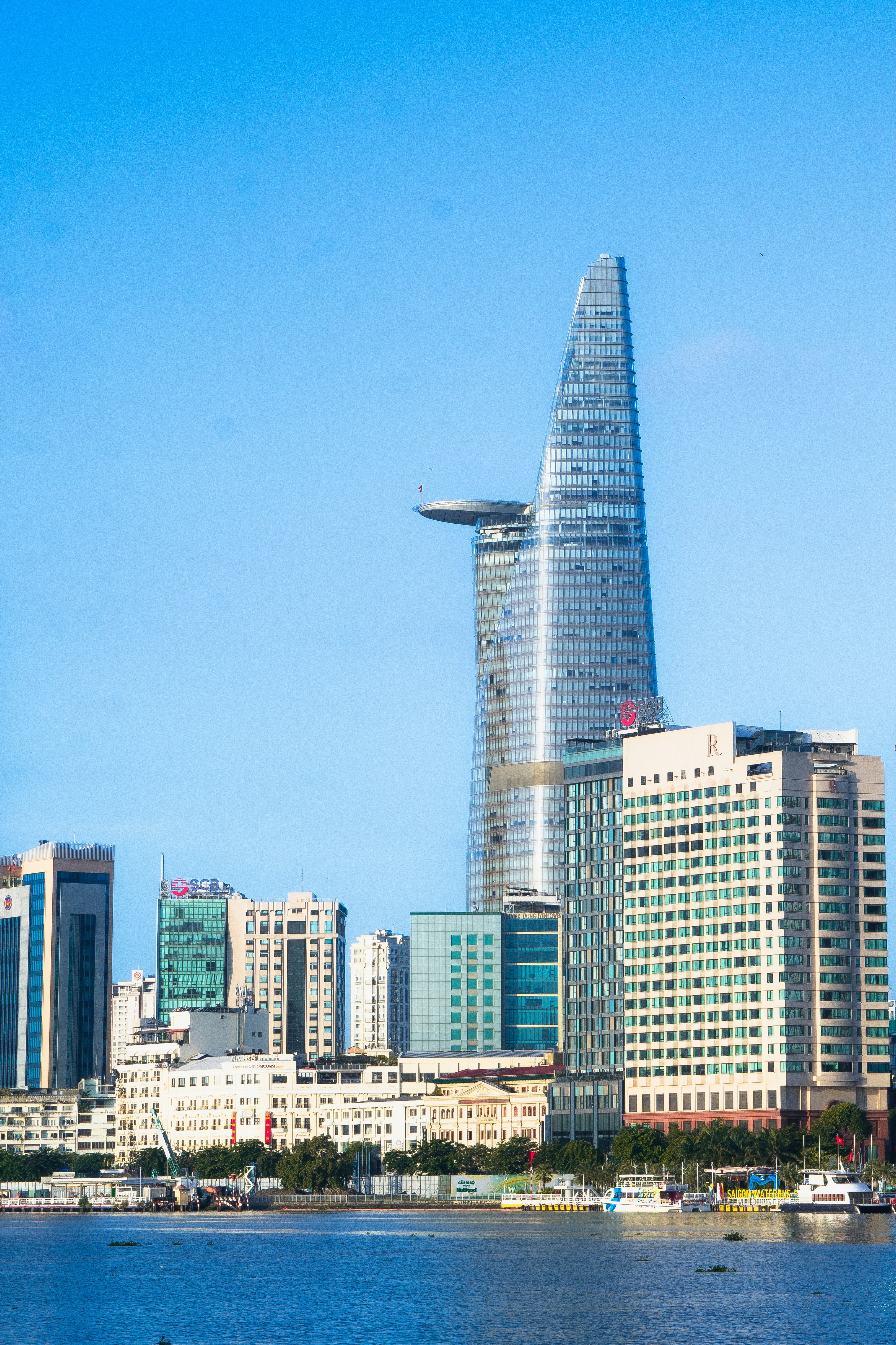 A sleek skyscraper towers over a bustling cityscape, reflecting modern design against a clear blue sky. The scene captures the essence of urban growth and innovation.
