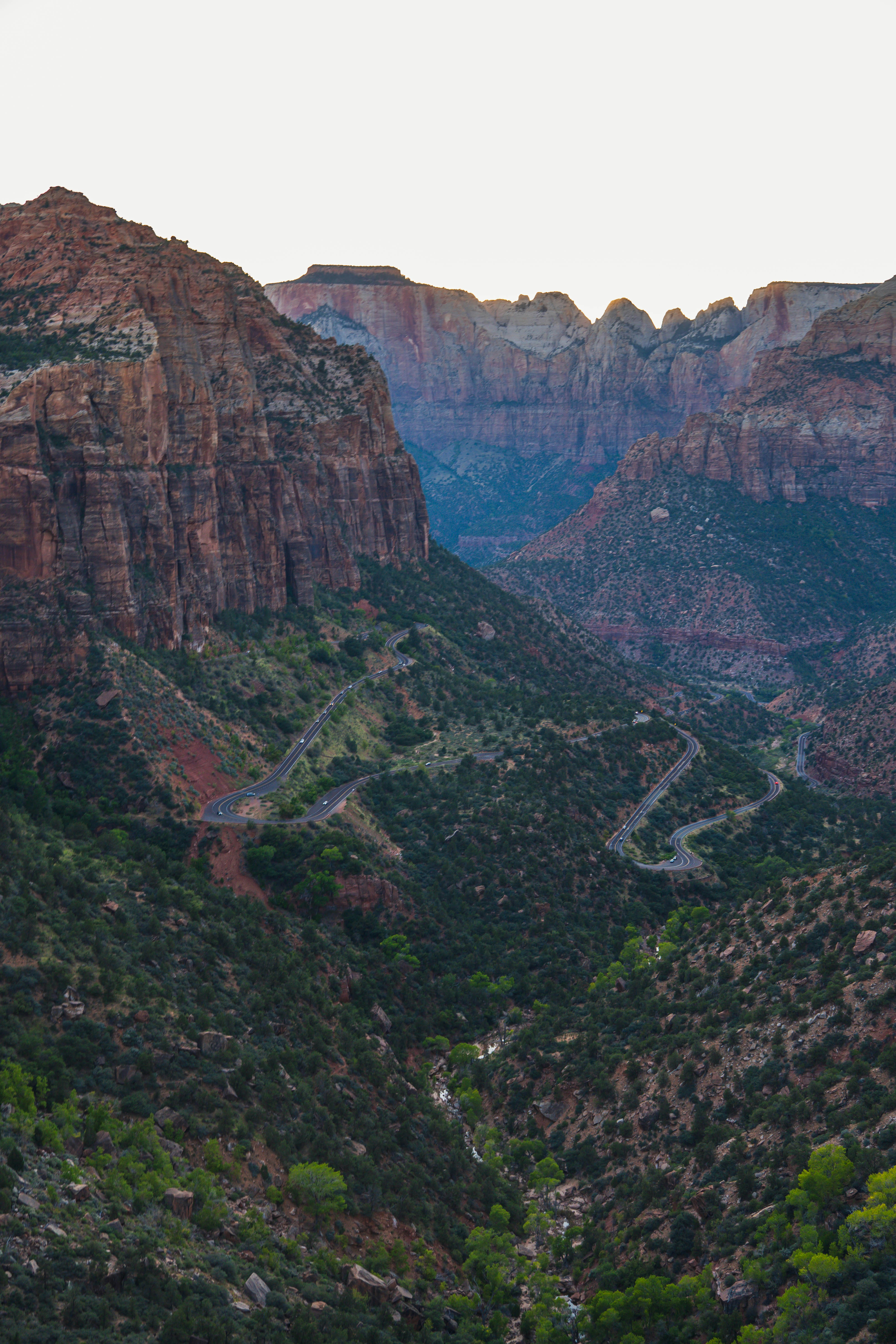 Winding road through a vast canyon landscape at dusk