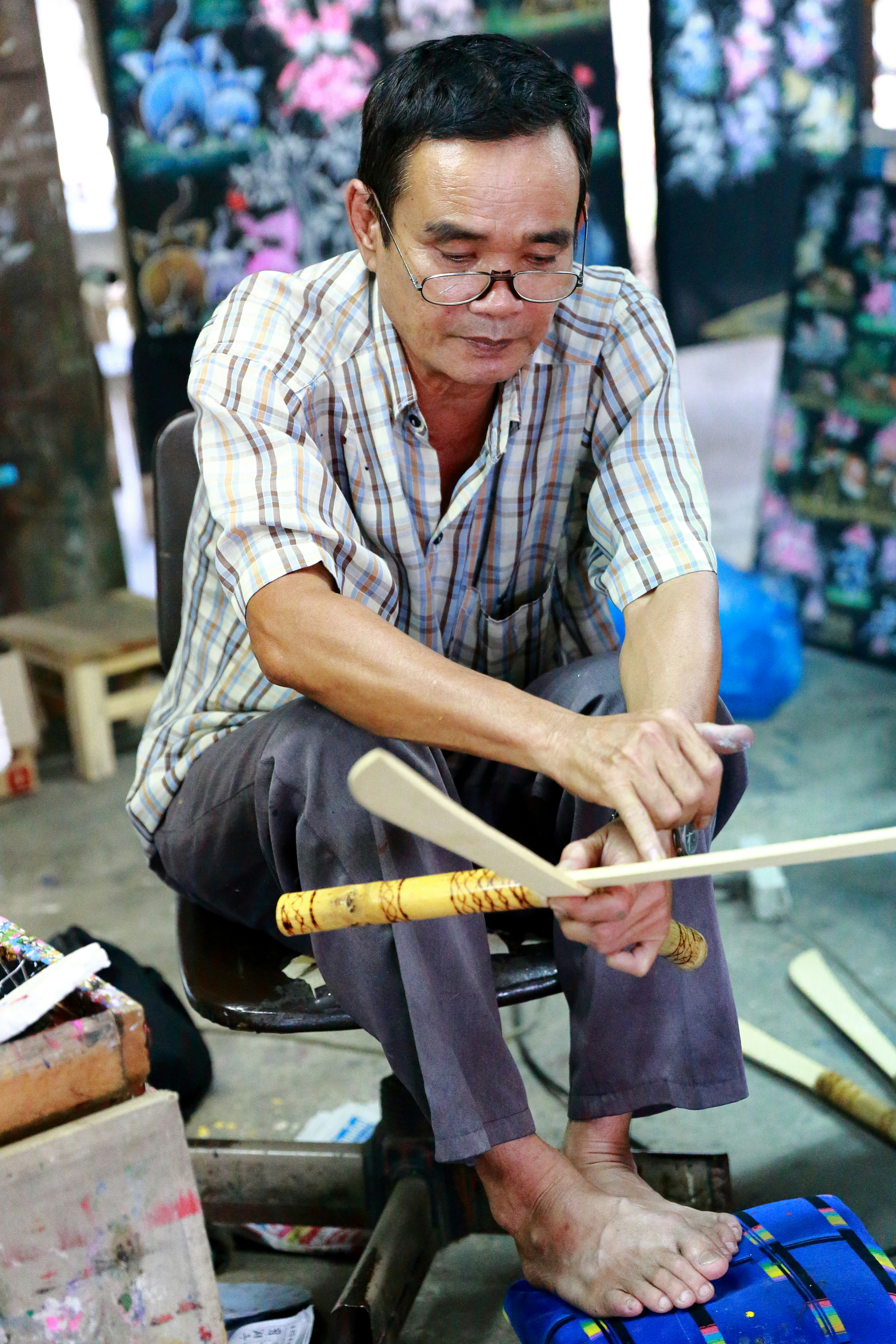 Man sitting and holding wooden tools