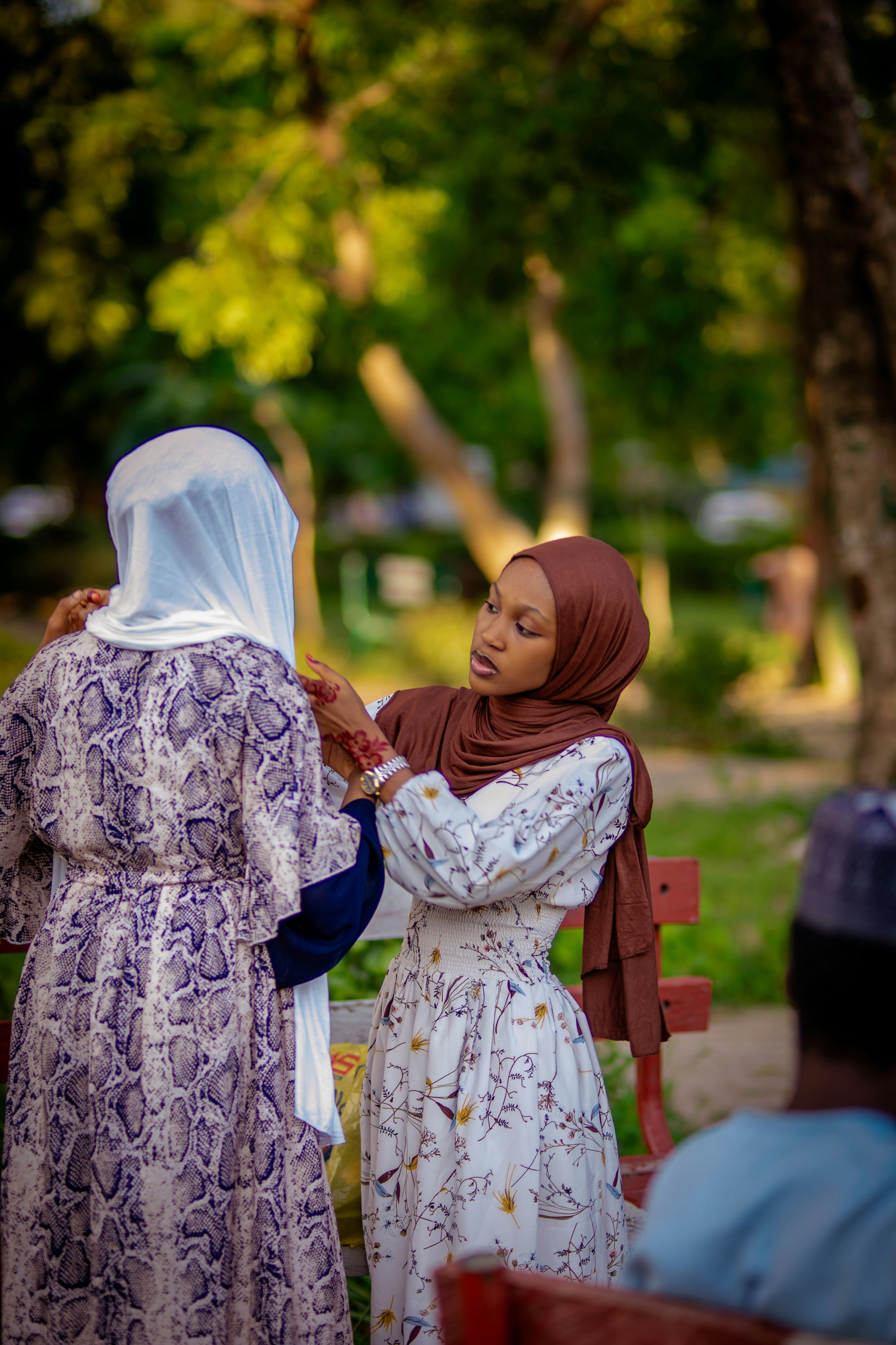 A clean and modern shot captured with natural light, highlighting fine details and balanced composition. Perfect for use in design projects, branding, and creative inspiration. | Two women in hijabs interacting in a park.