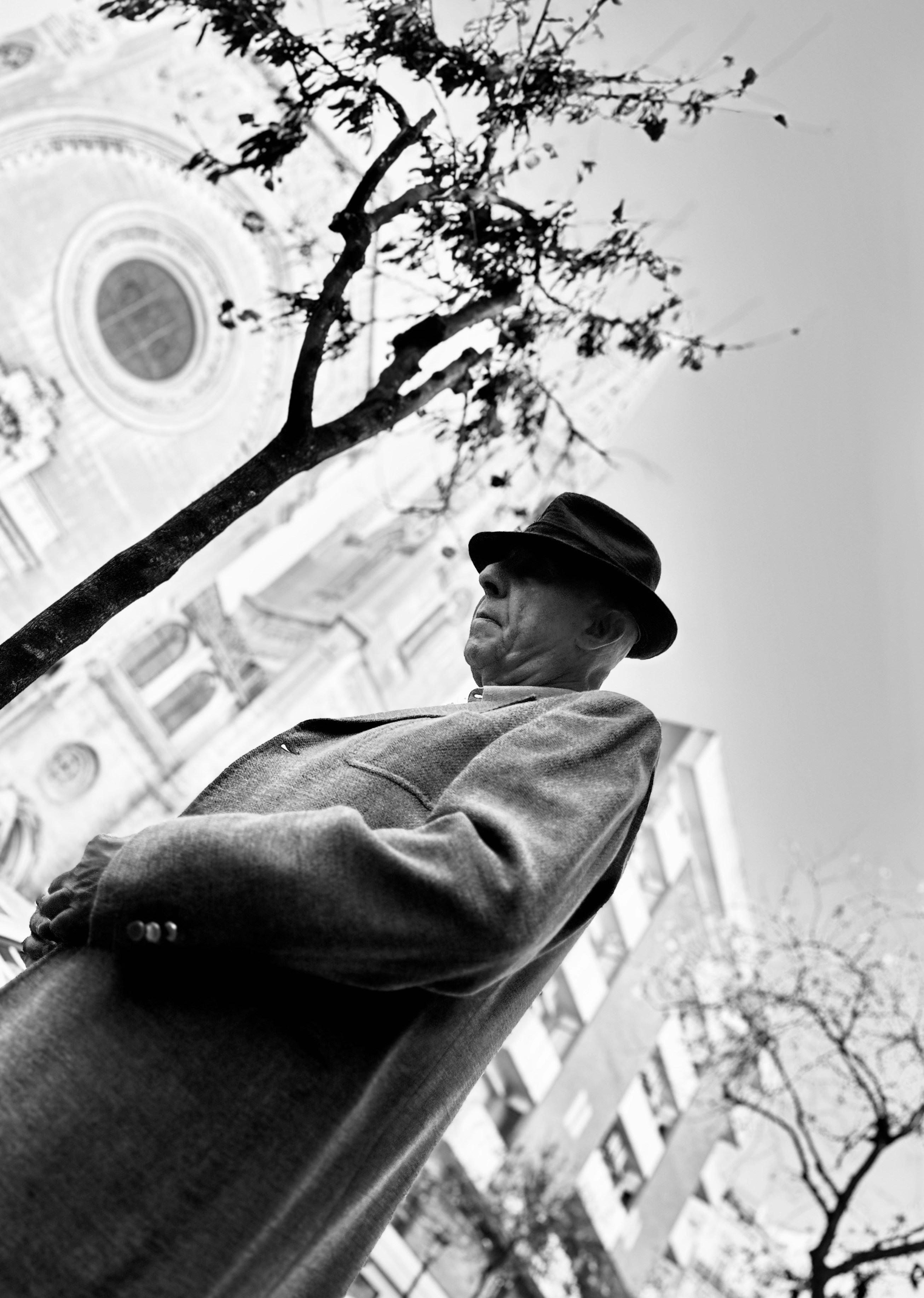 Man in hat and coat looking away outdoors.