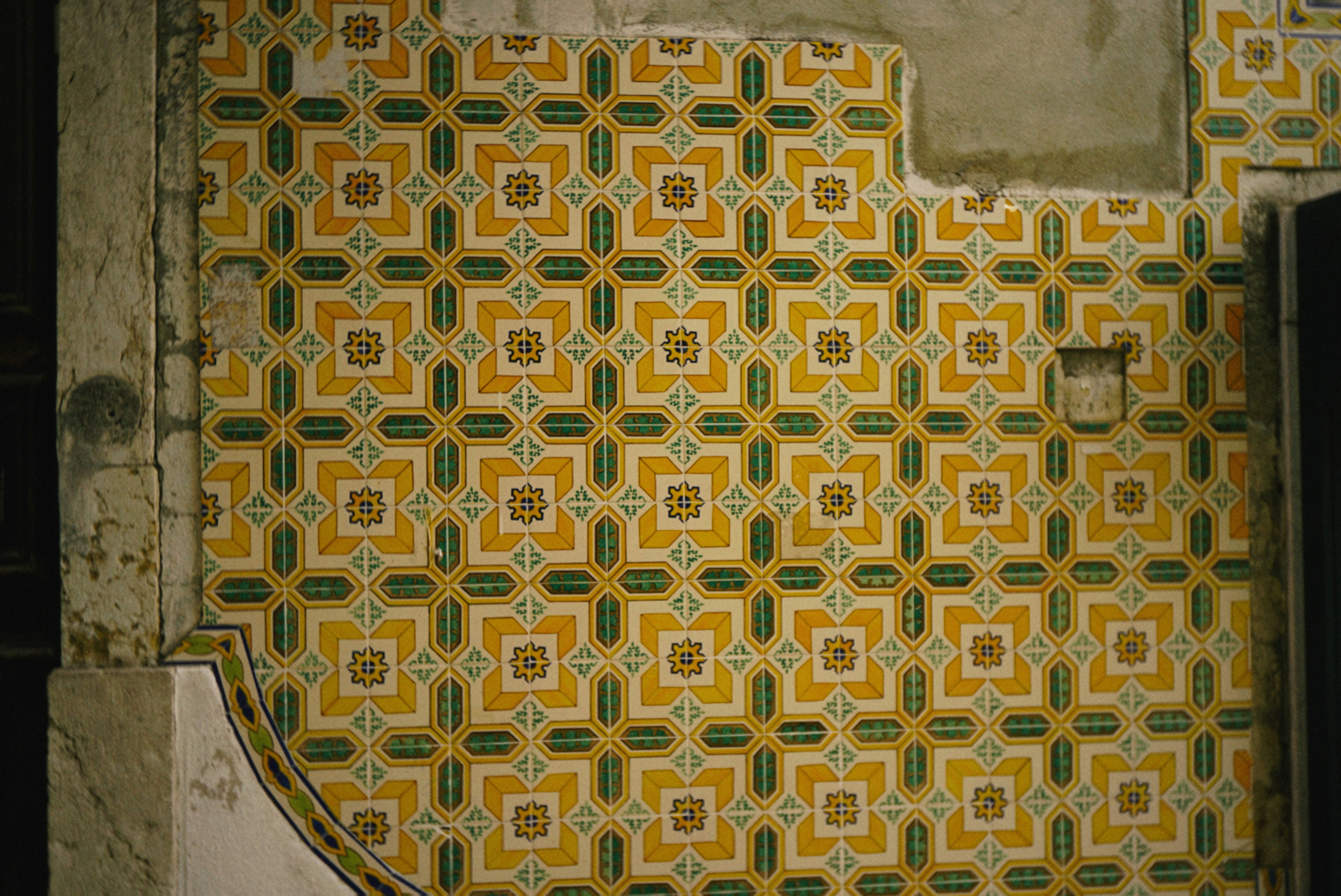 Yellow and green patterned tiles on a wall.