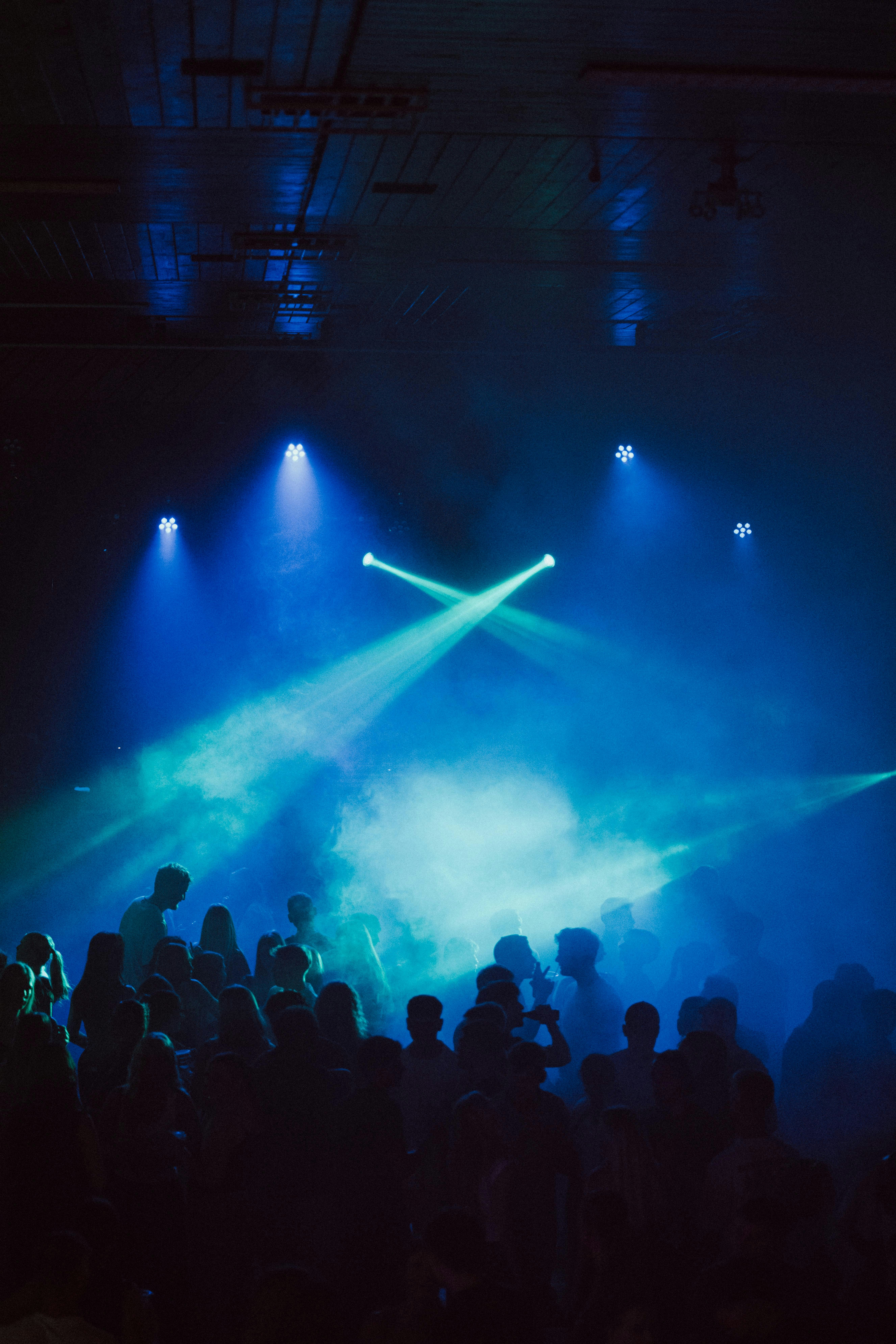 Crowd dancing under blue stage lights and smoke.
