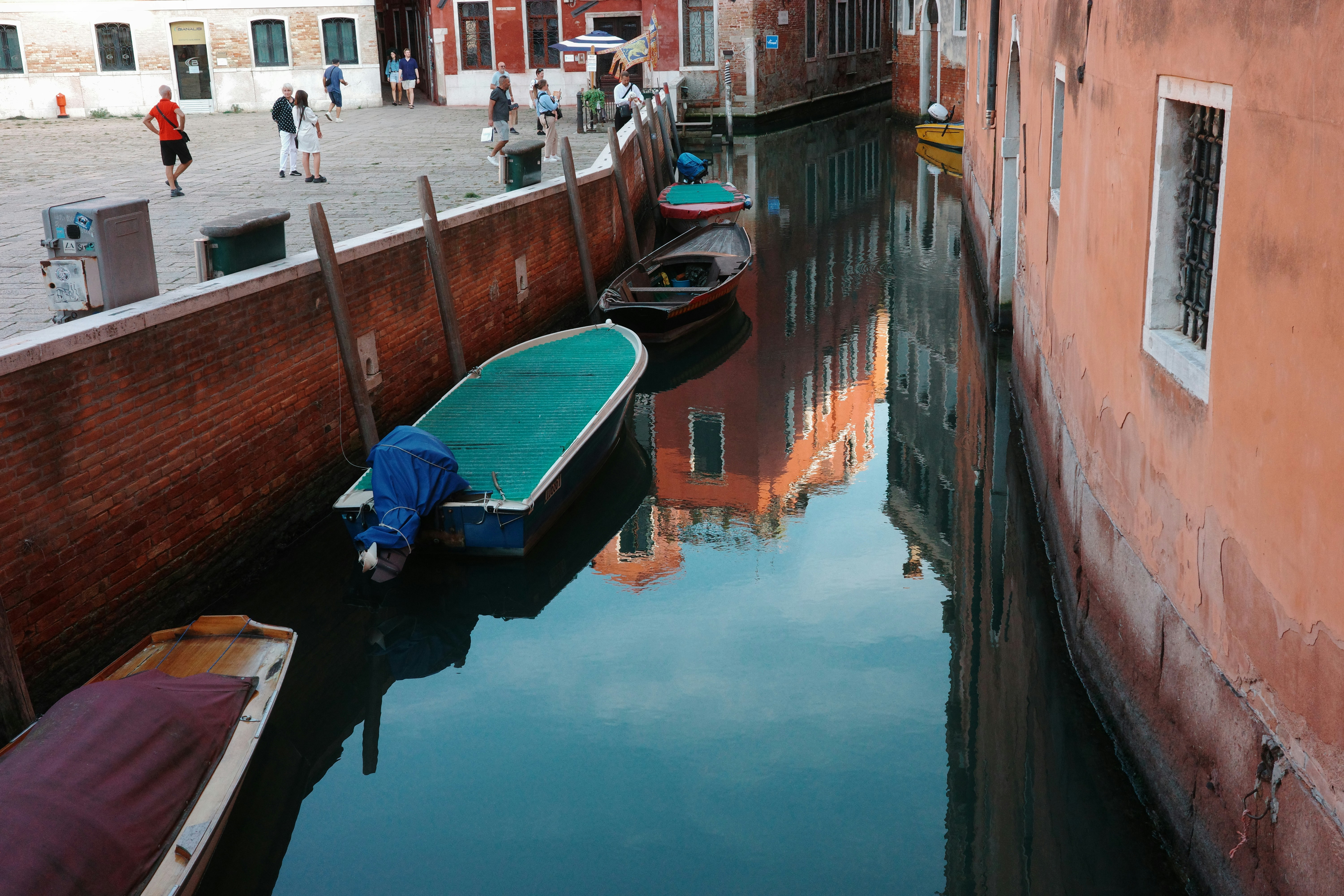 Colorful boats lined along a tranquil canal, reflecting the charming architecture of Venice. The scene captures the serene atmosphere of the city's waterways.