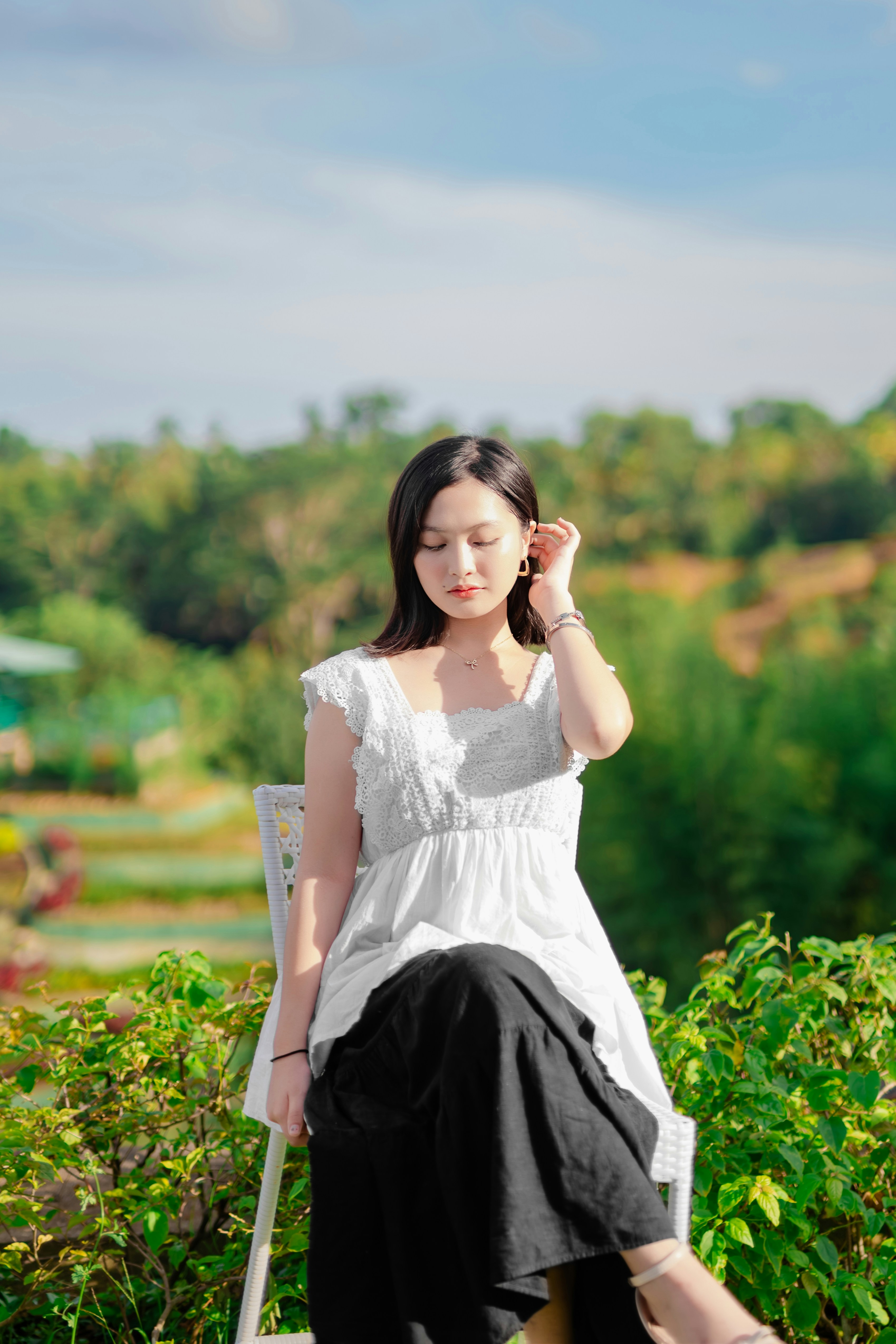 Young woman in white dress sitting outdoors
