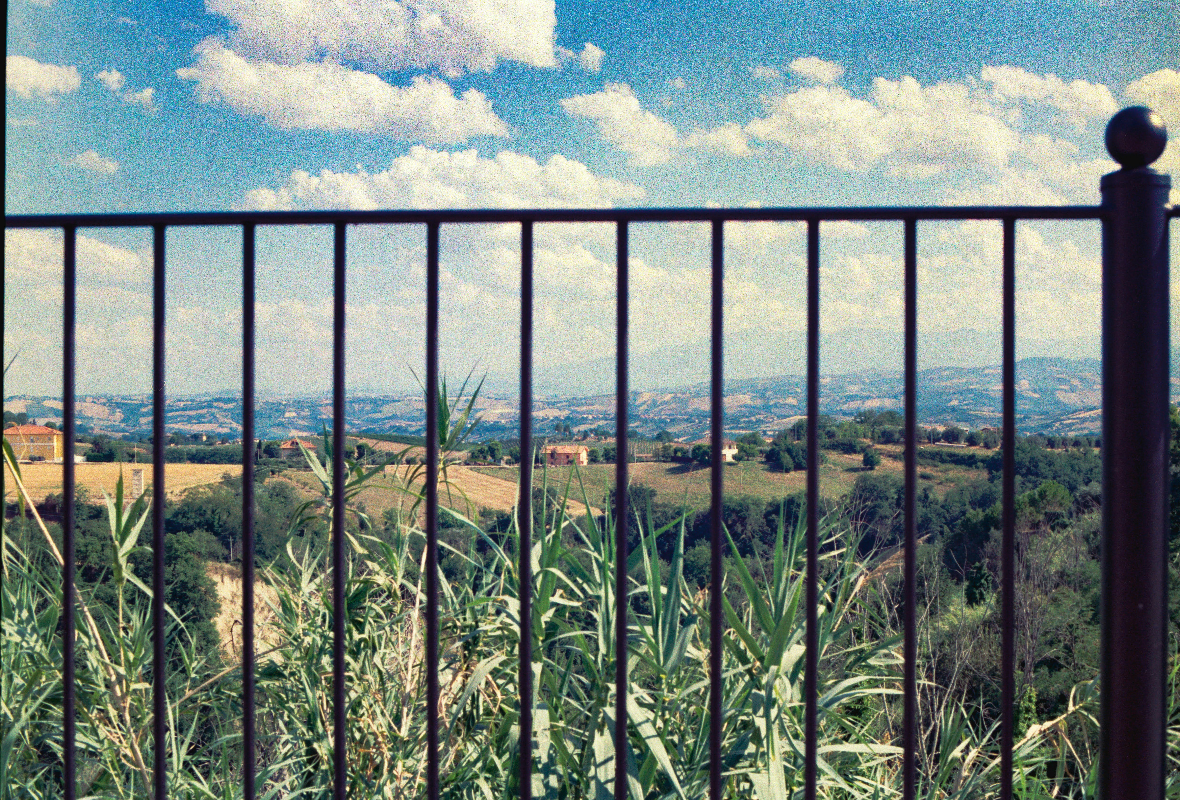 Rolling hills and fields seen through a fence