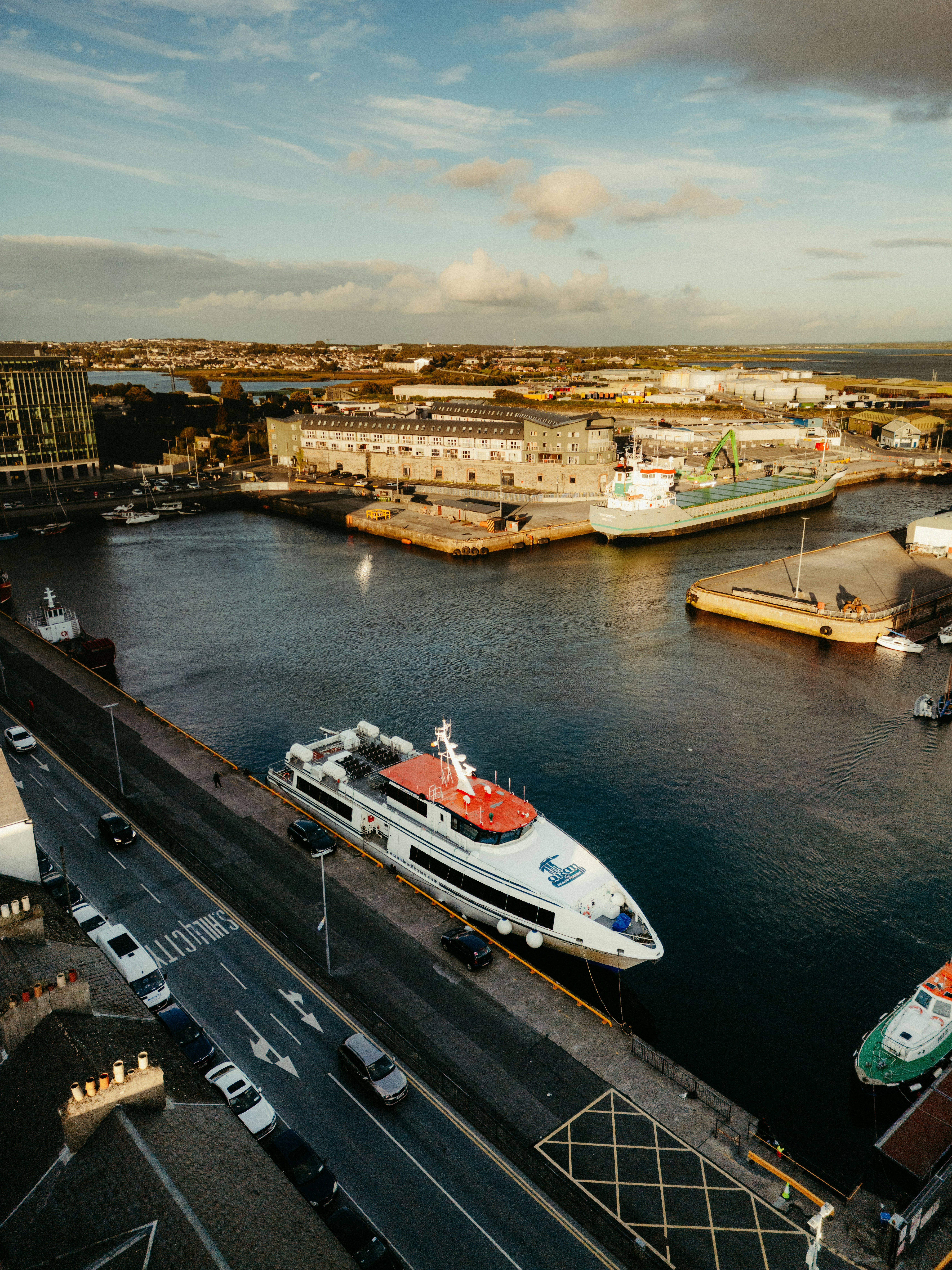 Ferry docked at a busy harbor with city buildings.