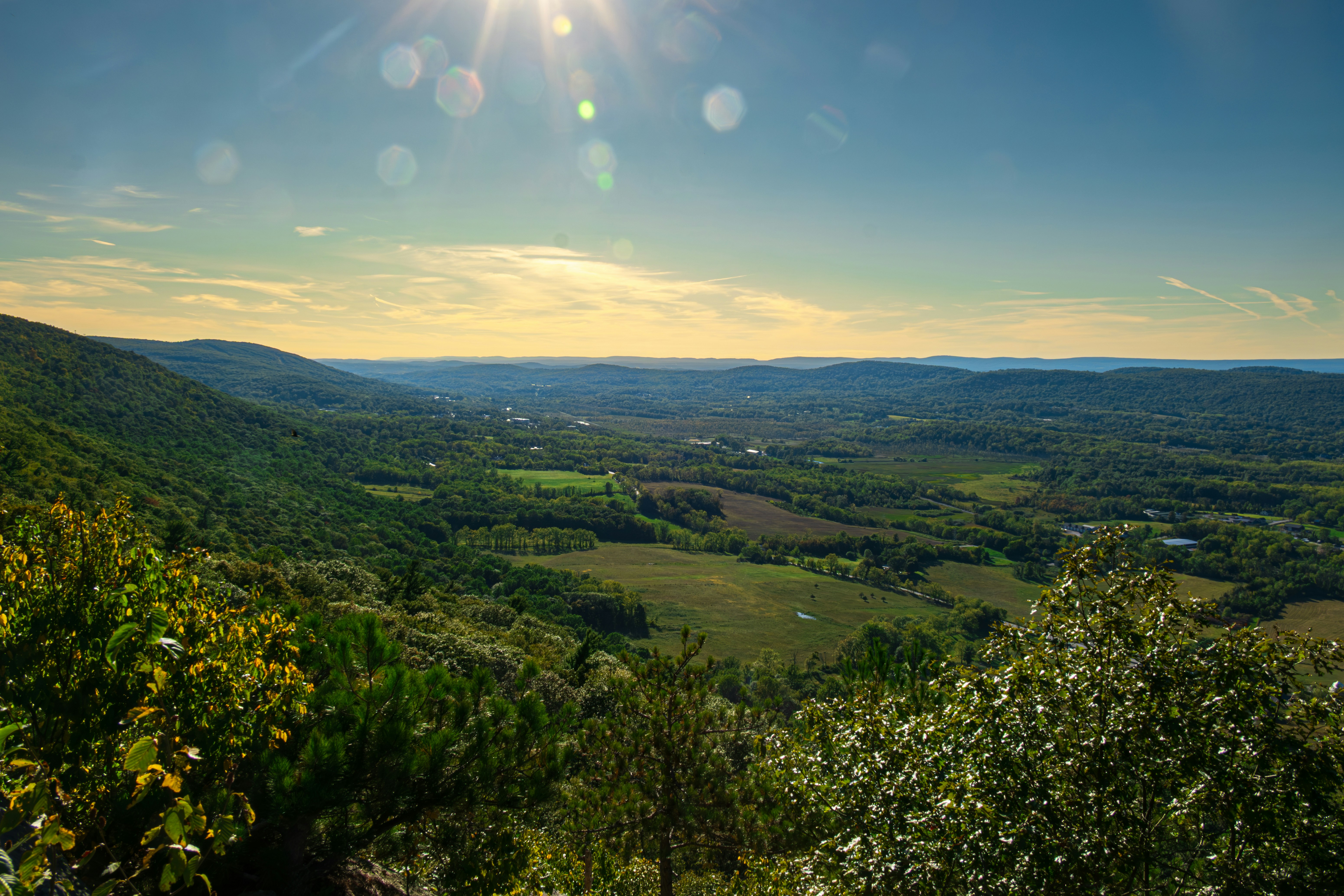 view from the top of stairway to heaven trail | Sunlight shines over a vast green valley landscape.