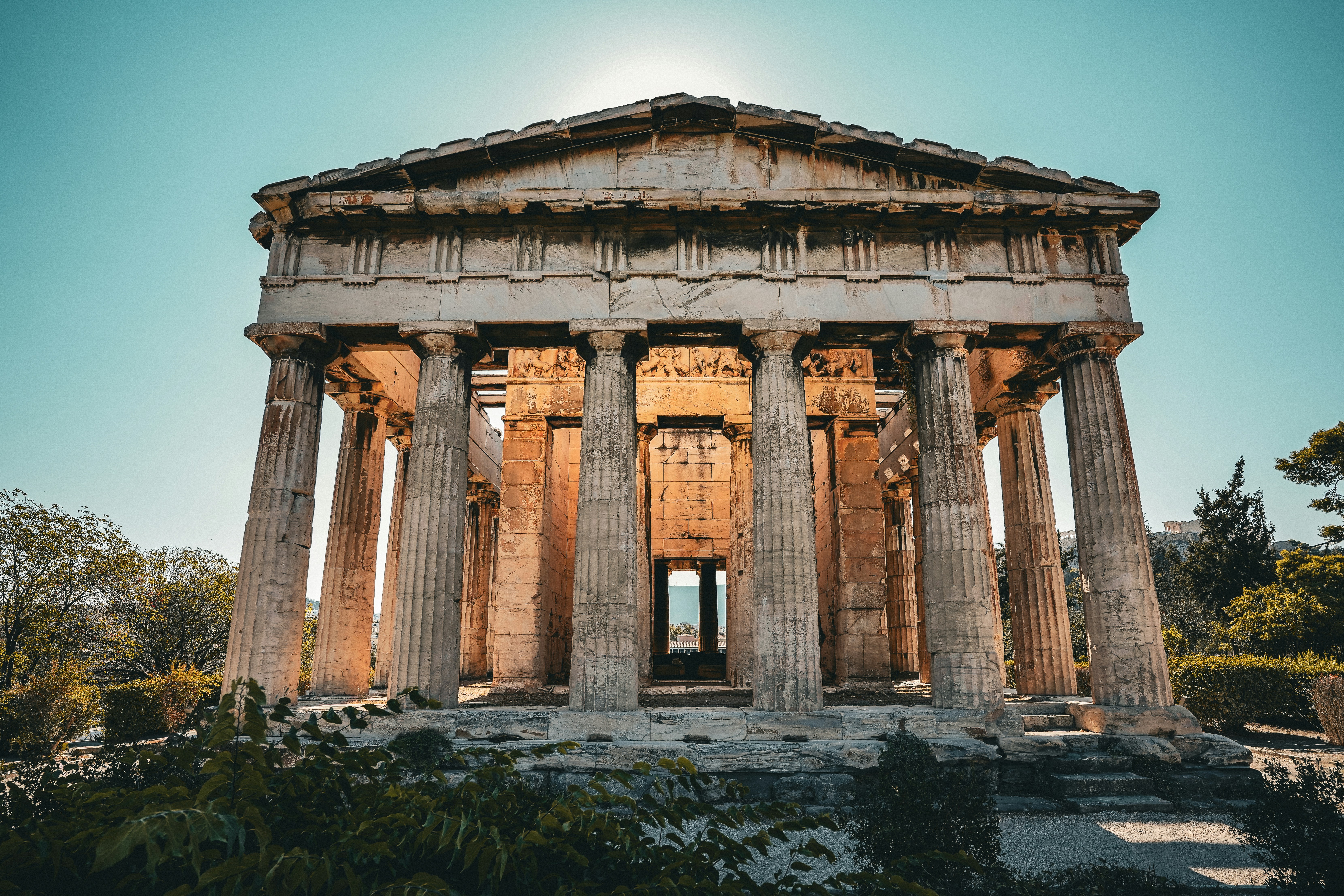 The Temple of Hephaestus, built around 449 BCE, stands as one of the best-preserved ancient temples in Greece. Overlooking the Agora of Athens, it was dedicated to the god of fire and craftsmanship, fittingly located in the city’s artisan quarter. Its enduring structure reflects the architectural brilliance of the Athenian Golden Age. | Ancient greek temple with large columns under blue sky.