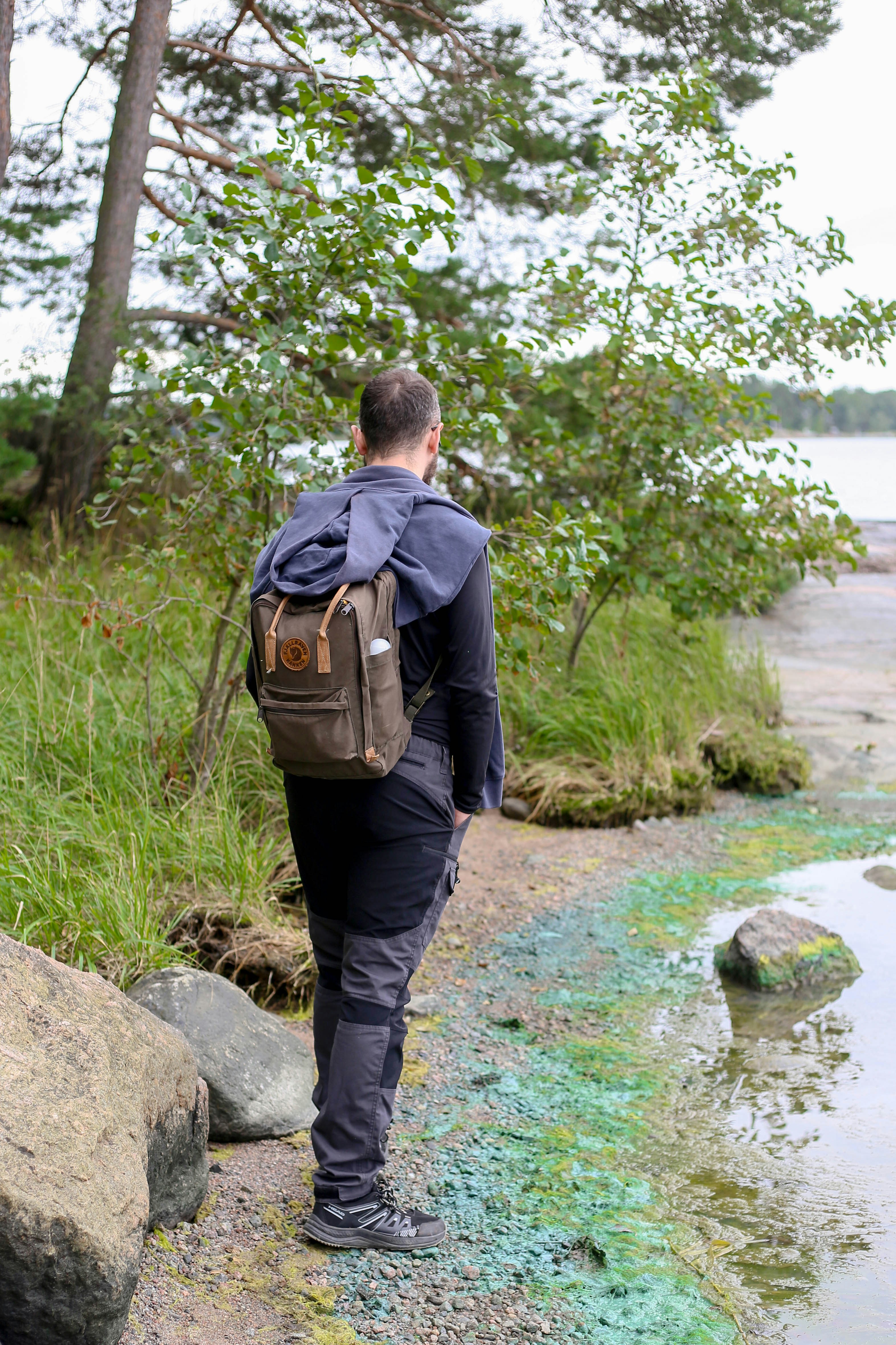 man at the lake | Man with backpack looking at colorful shoreline