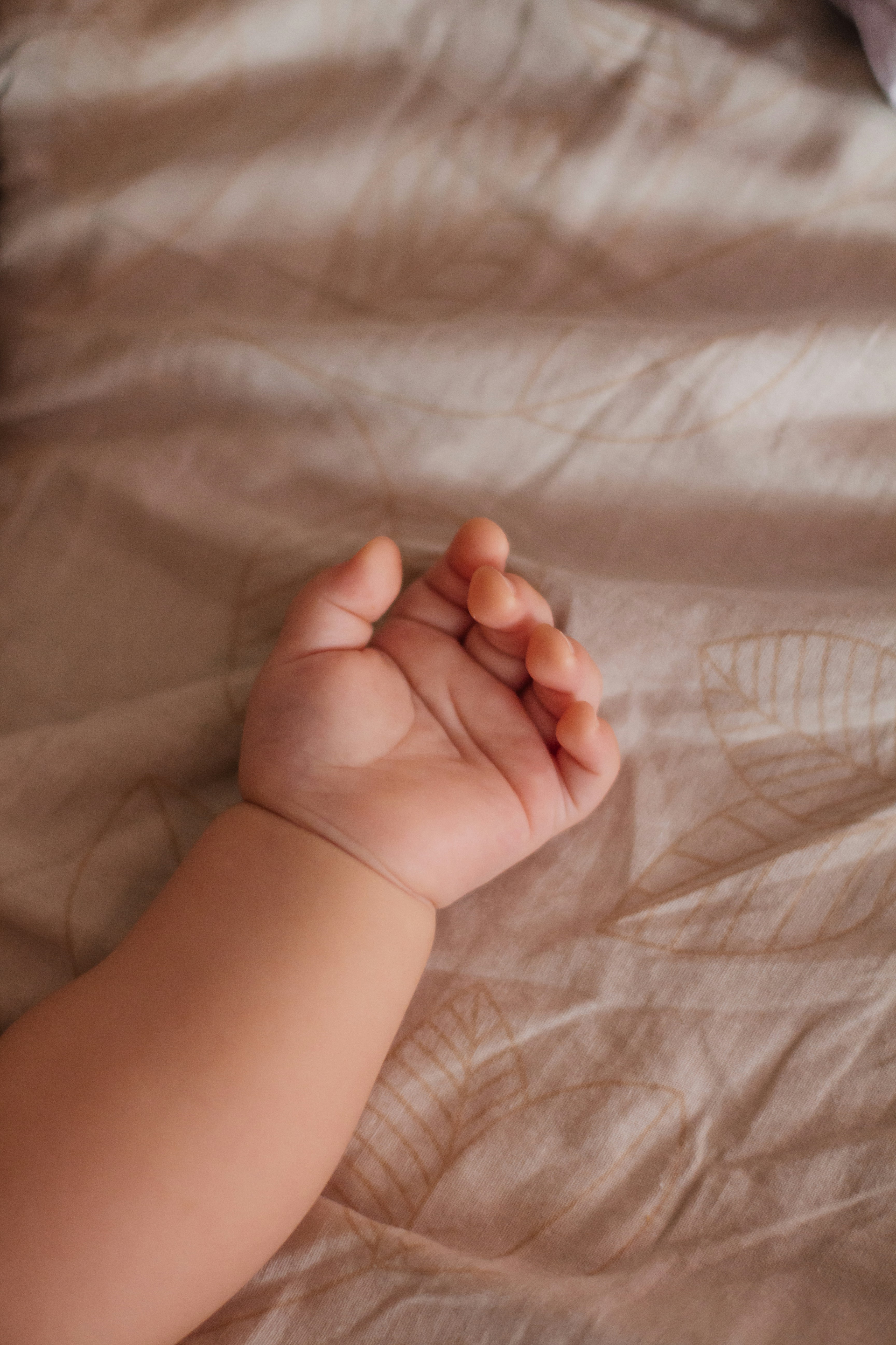 A baby's arm and hand resting on a textured blanket.