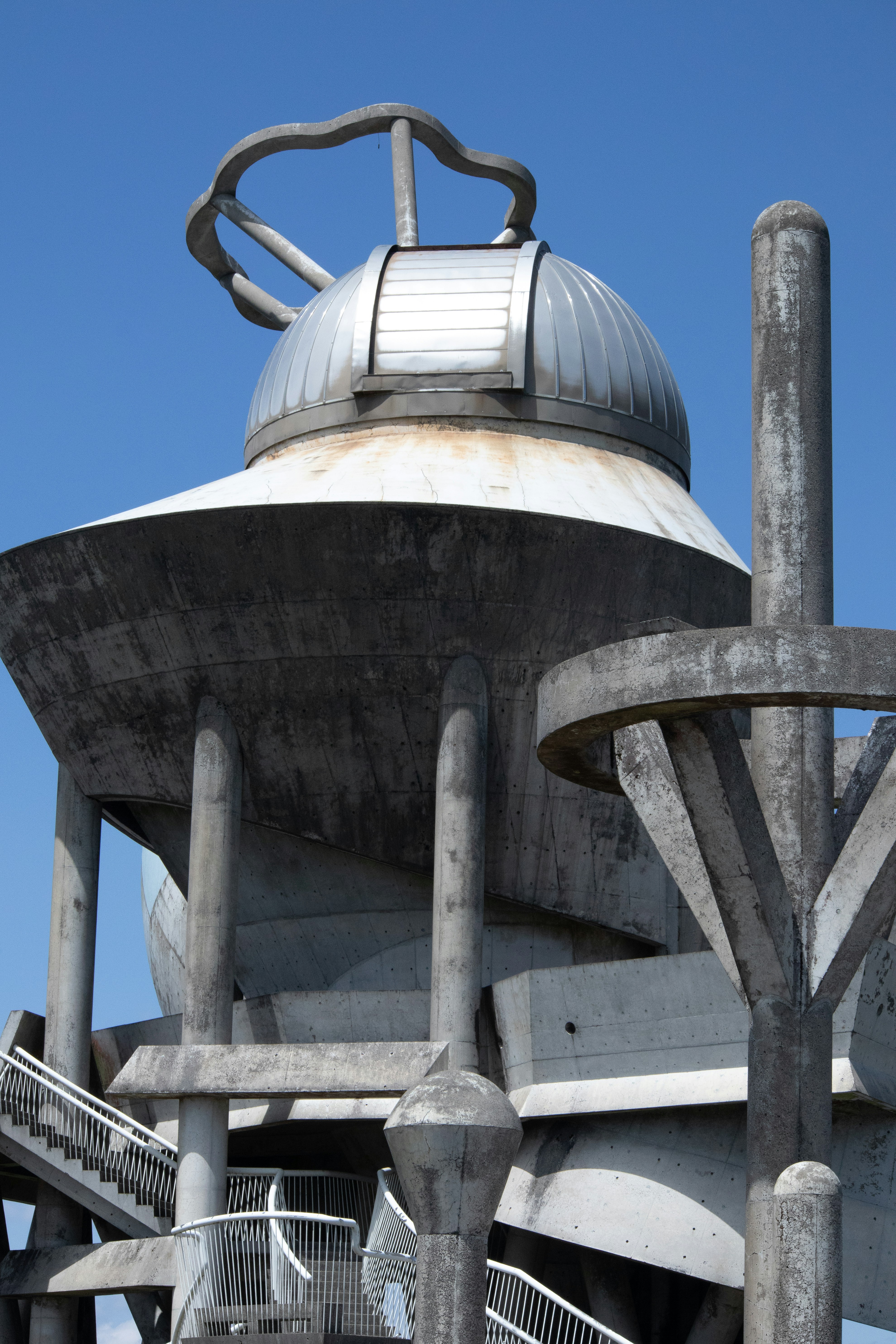 Modern concrete structure with observatory dome against blue sky