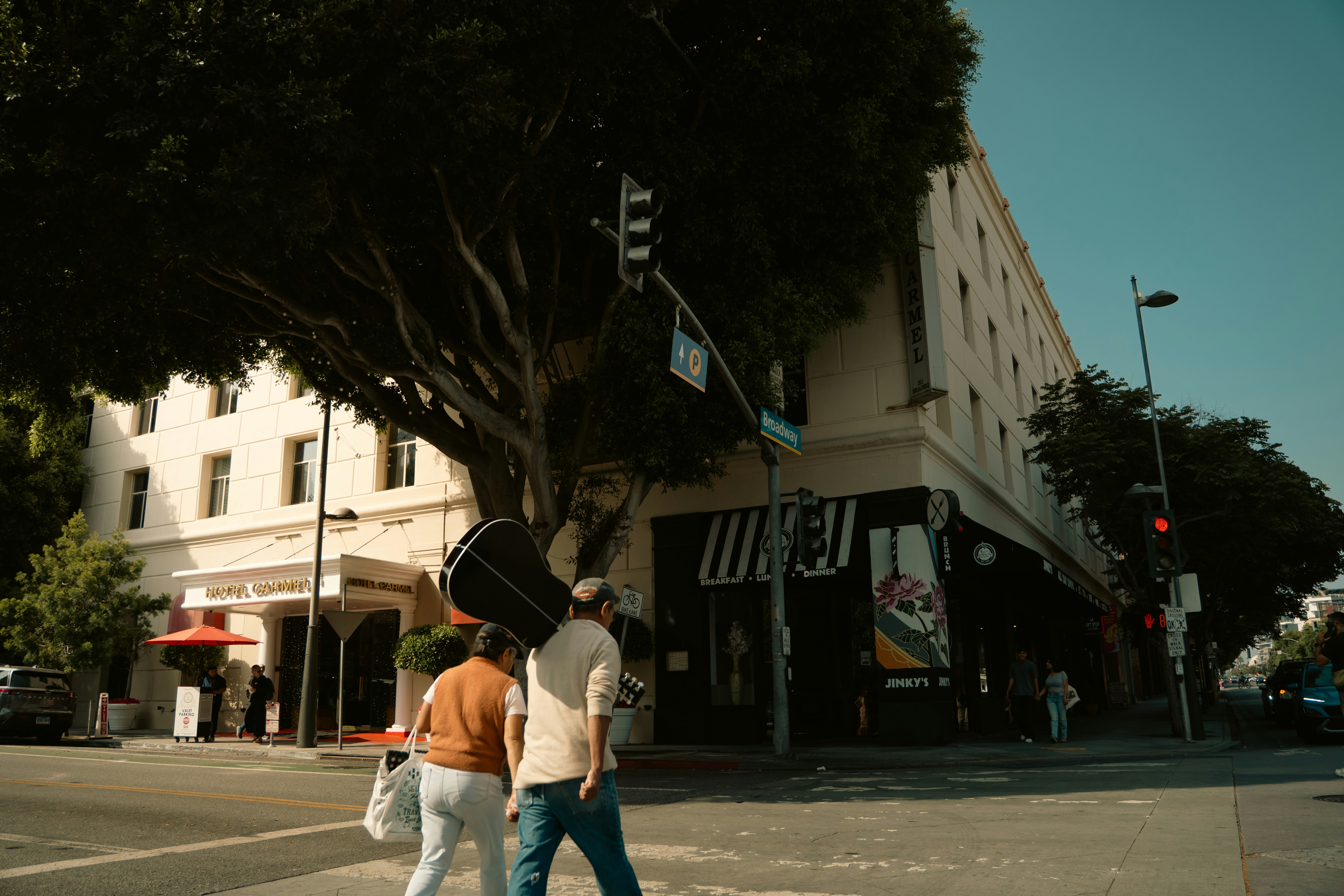 People carrying a guitar case across street