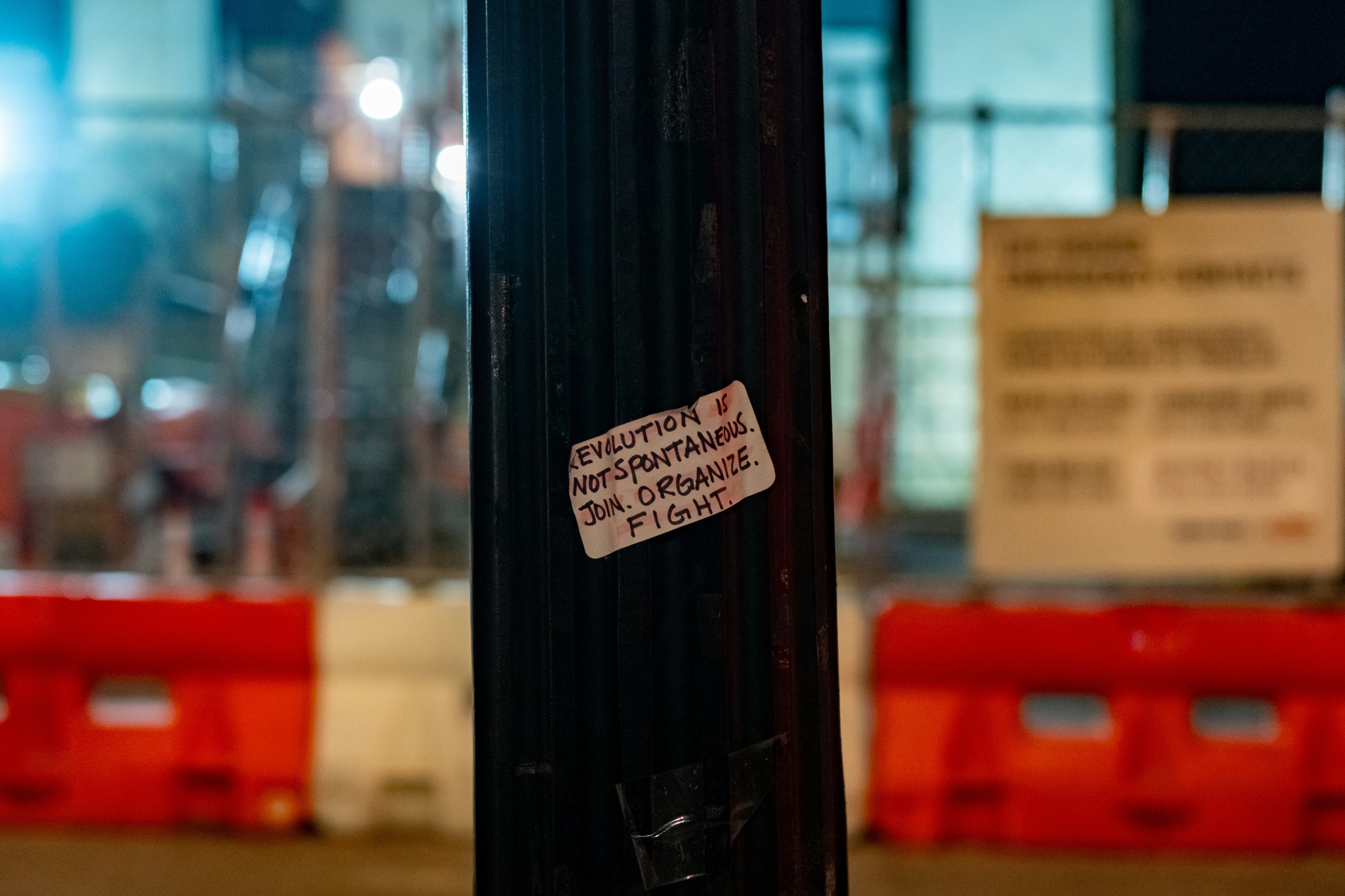 Sticker on a pole with construction barriers behind.