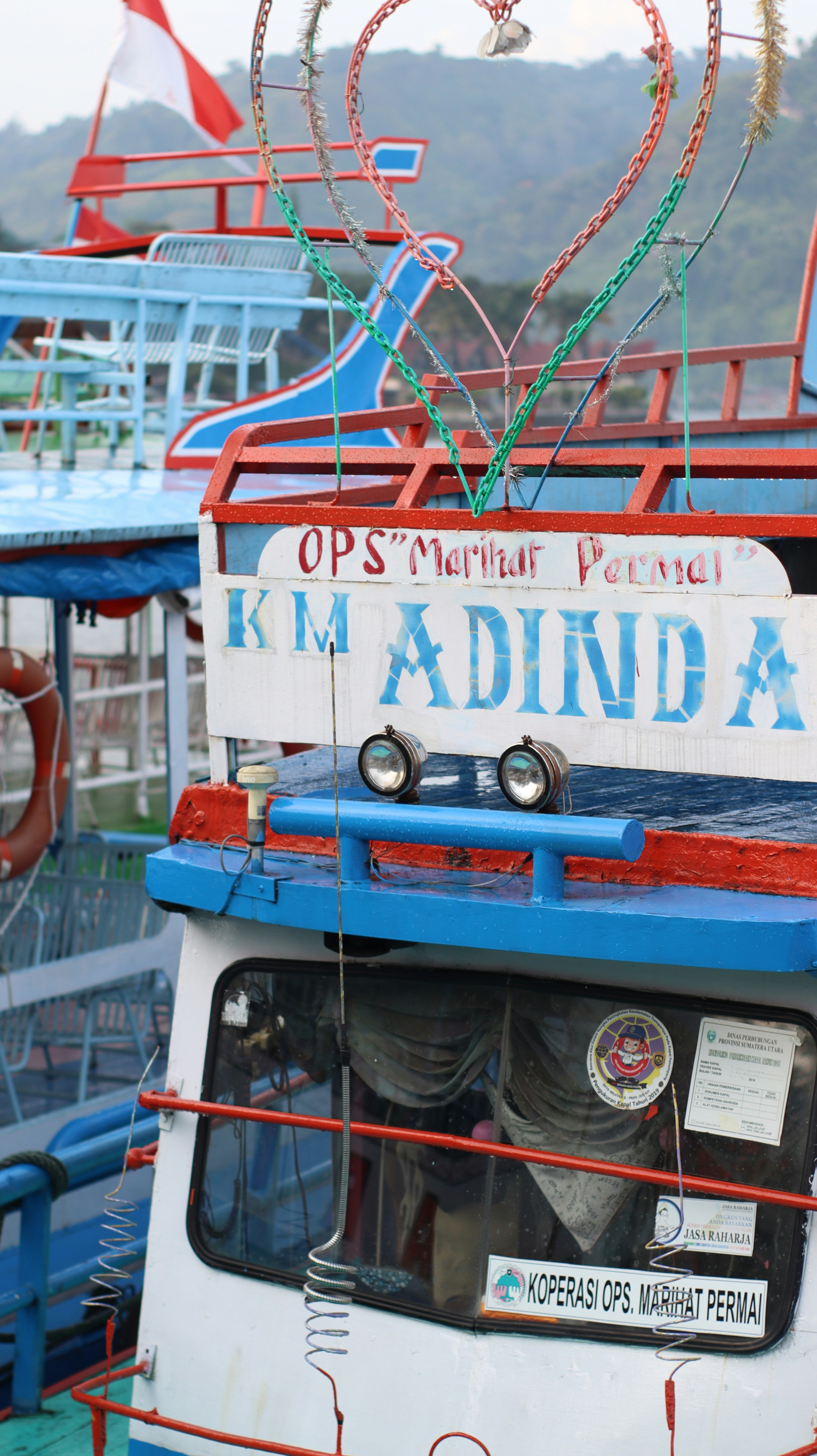 Colorful fishing boat named KM Adinda adorned with a heart-shaped decoration, showcasing local maritime culture and craftsmanship.
