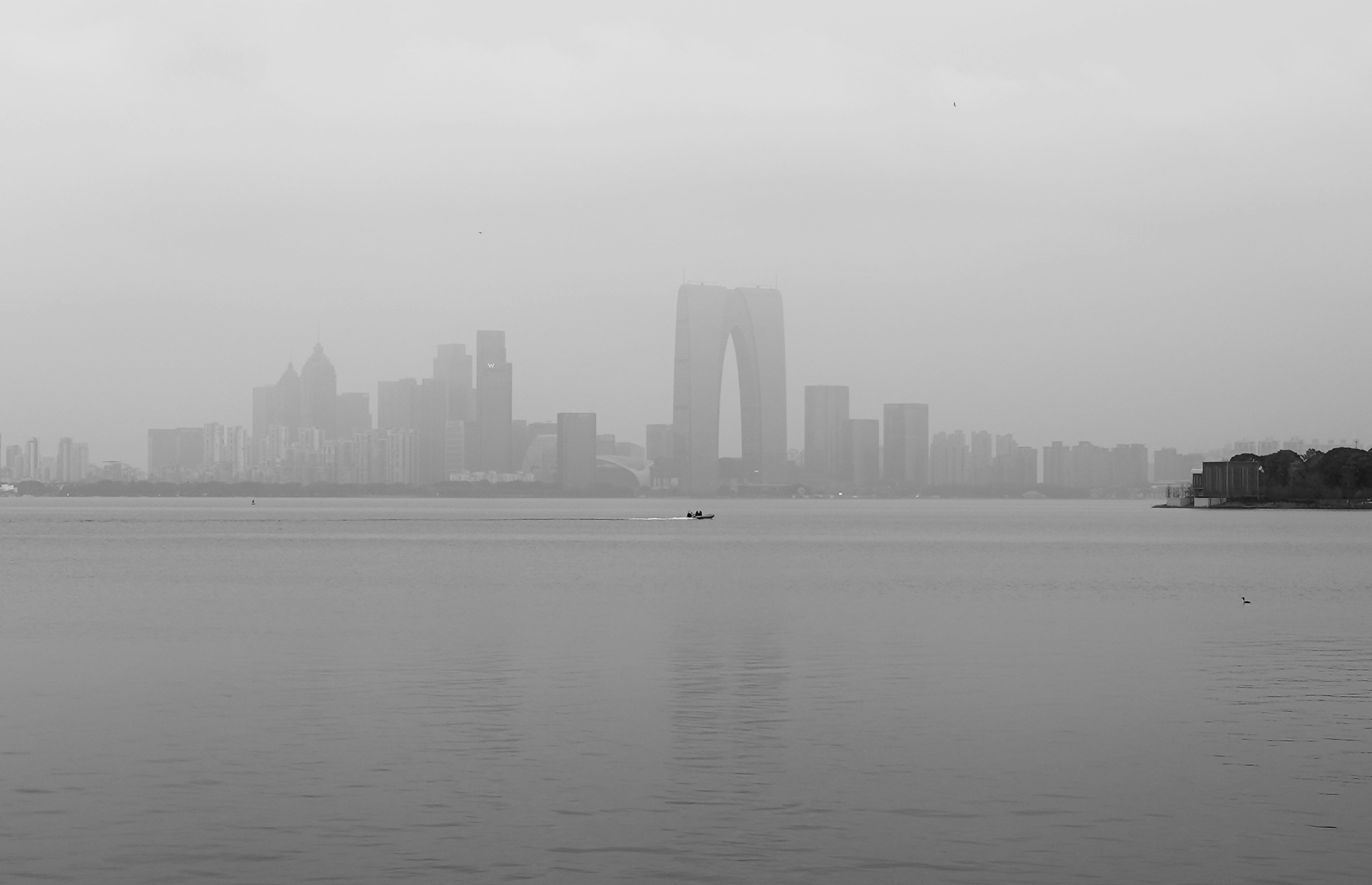 Misty cityscape with modern buildings across water.