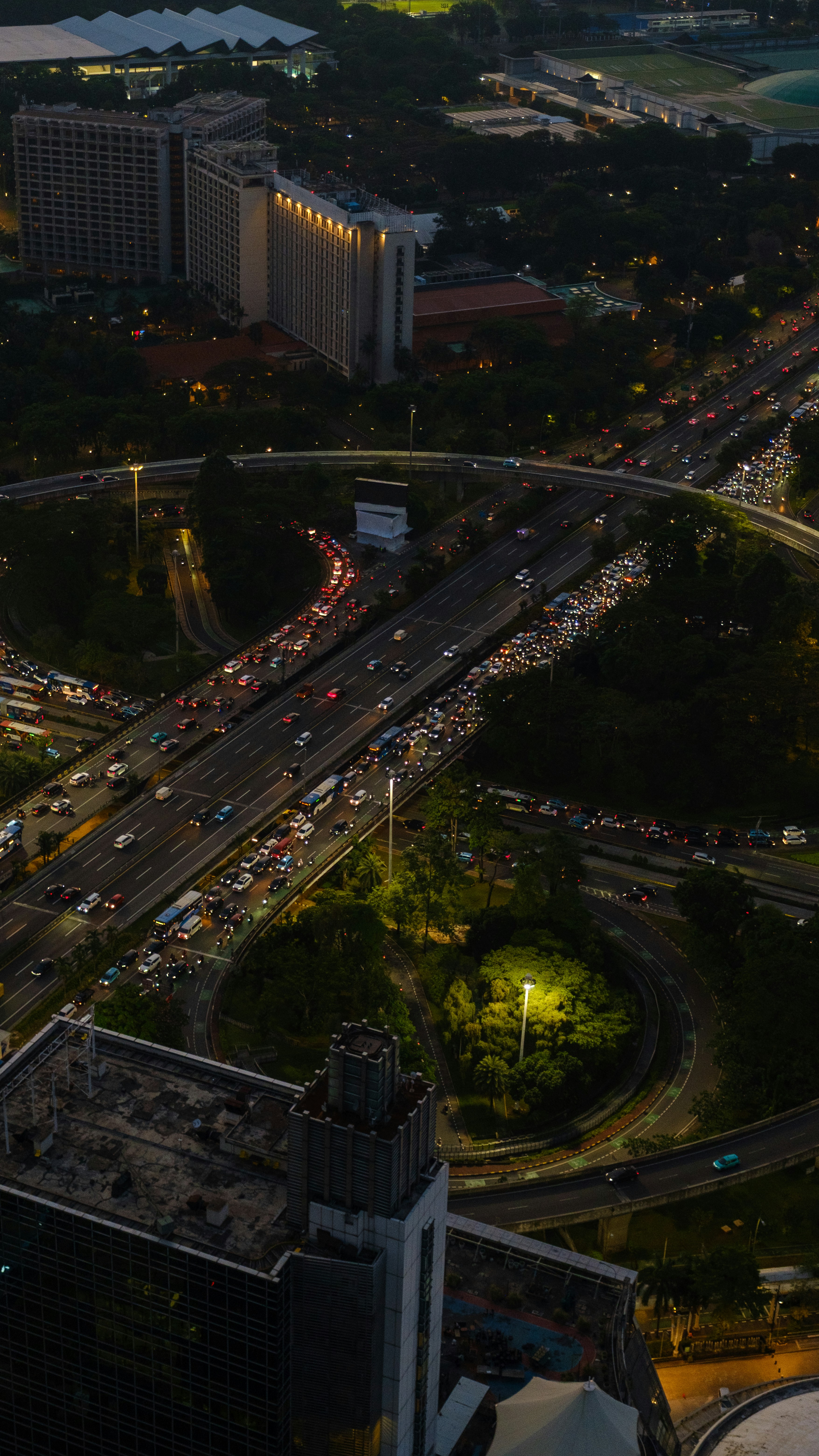 Aerial view of a bustling city intersection illuminated by streetlights, showcasing the flow of traffic amidst urban greenery.