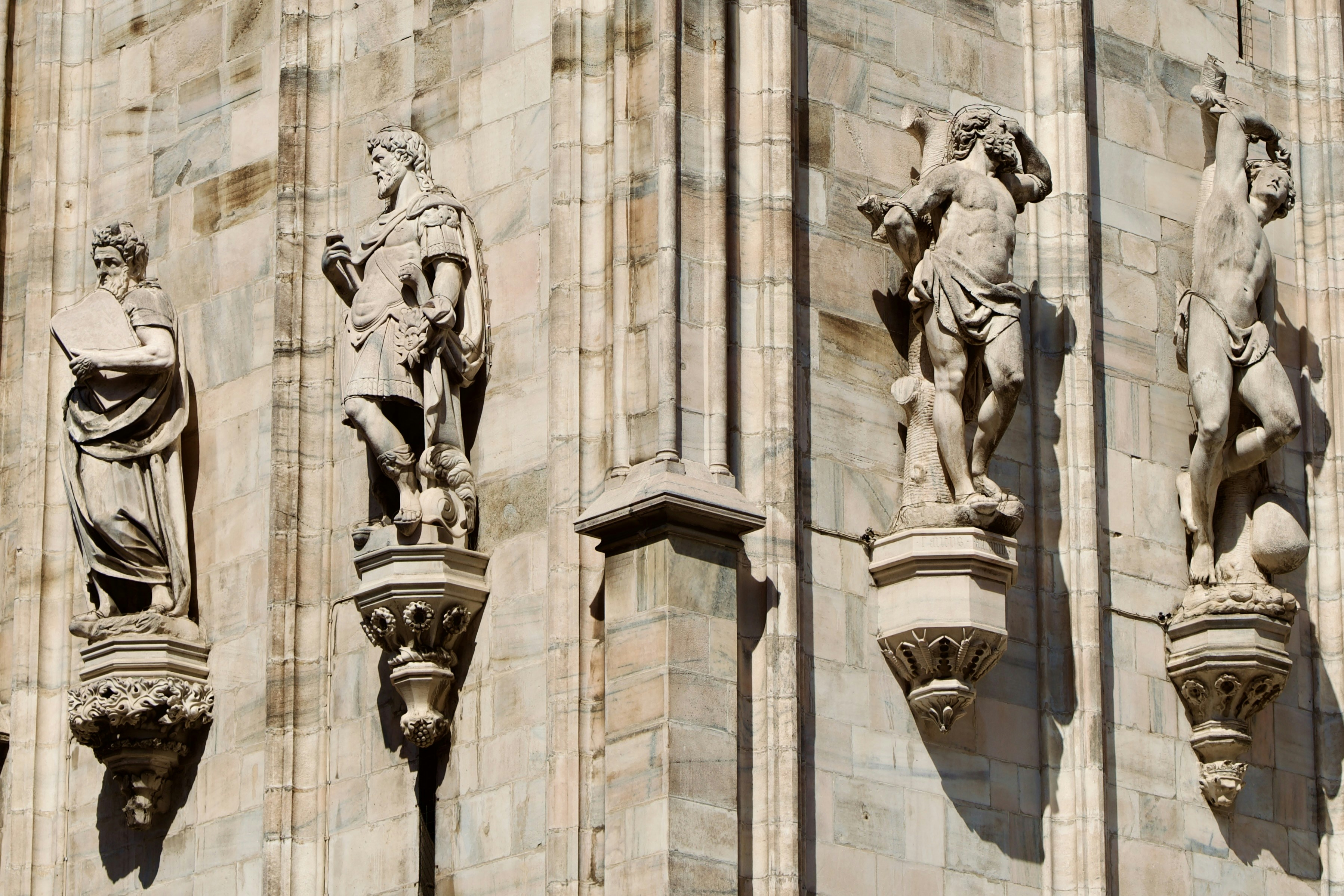 Four stone statues adorn a building's facade.