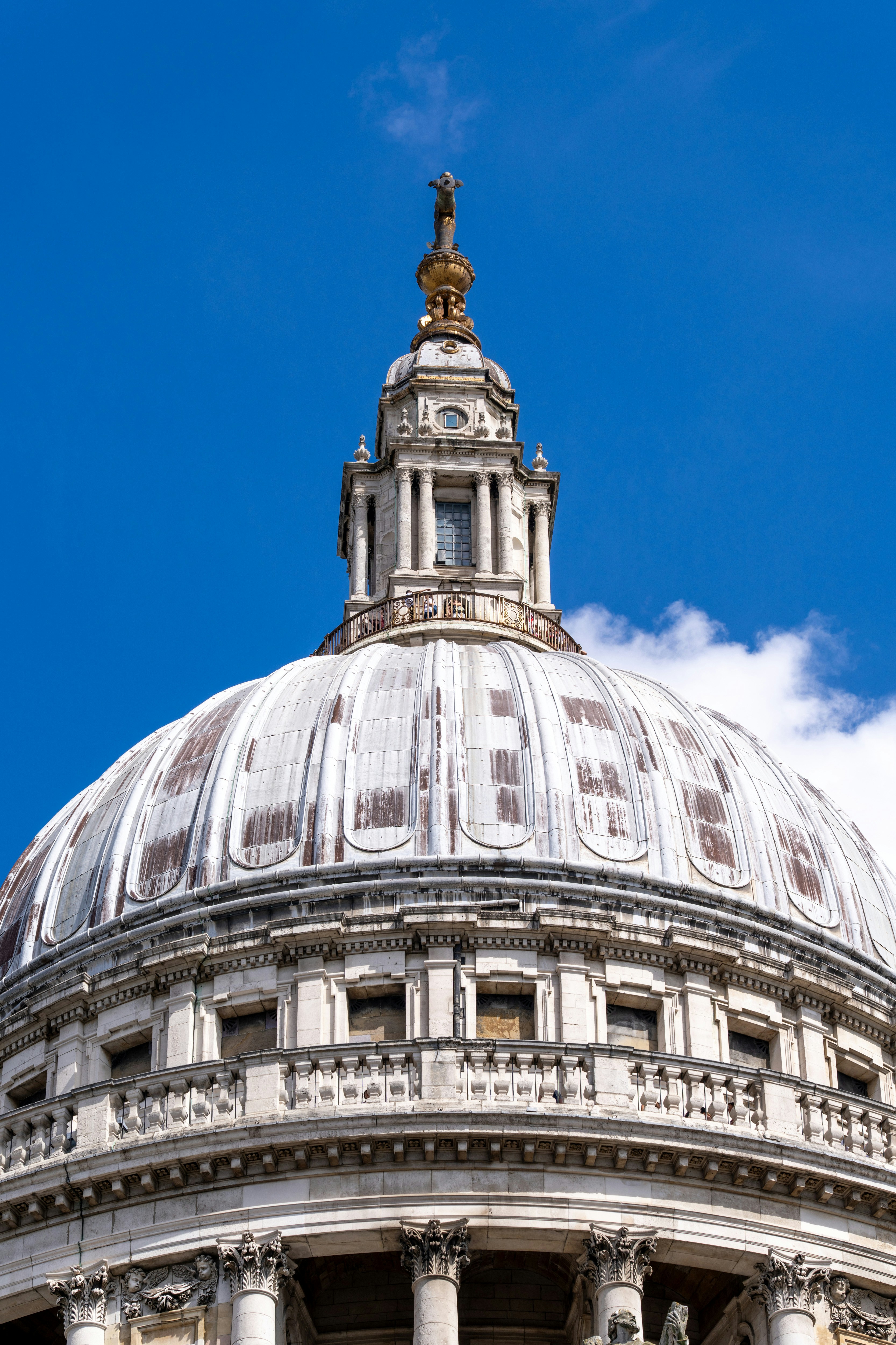 The iconic dome of St. Paul's Cathedral rises majestically against a clear blue sky, showcasing intricate architectural details and a prominent statue atop.