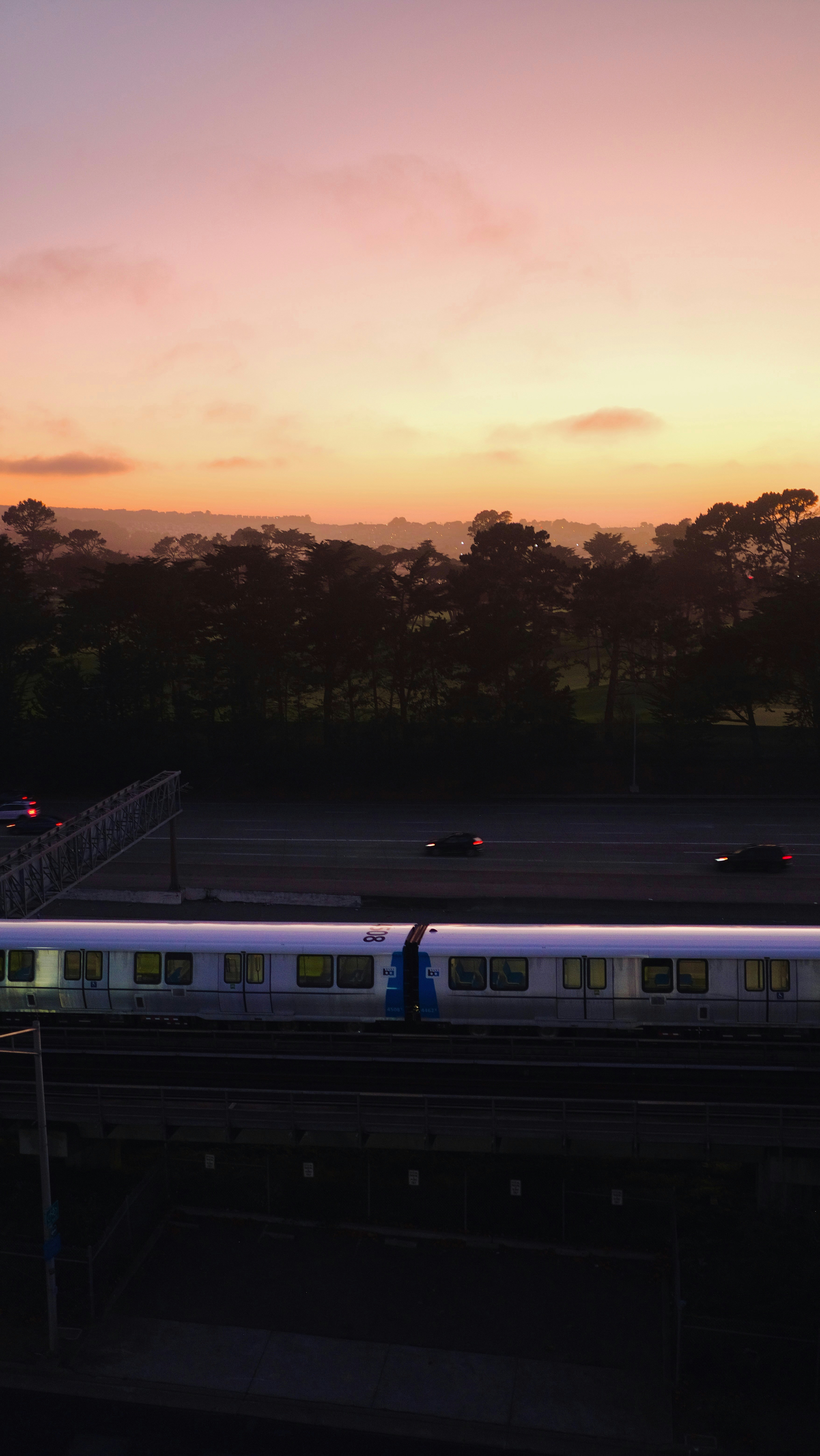 Twilight Rails: A Train Crossing Quiet Highways Beneath a Peach Sky