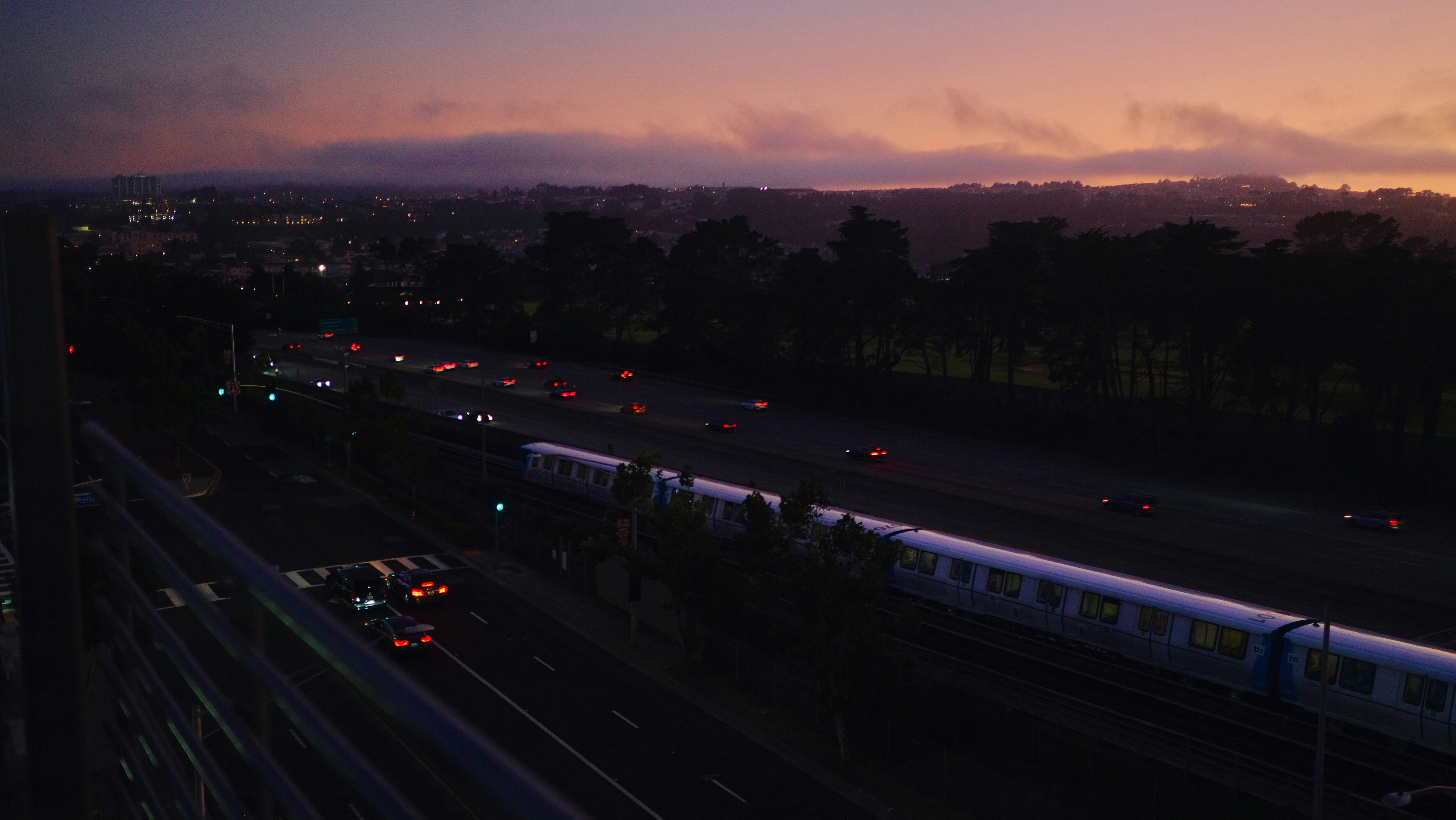 Train traveling on highway at dusk